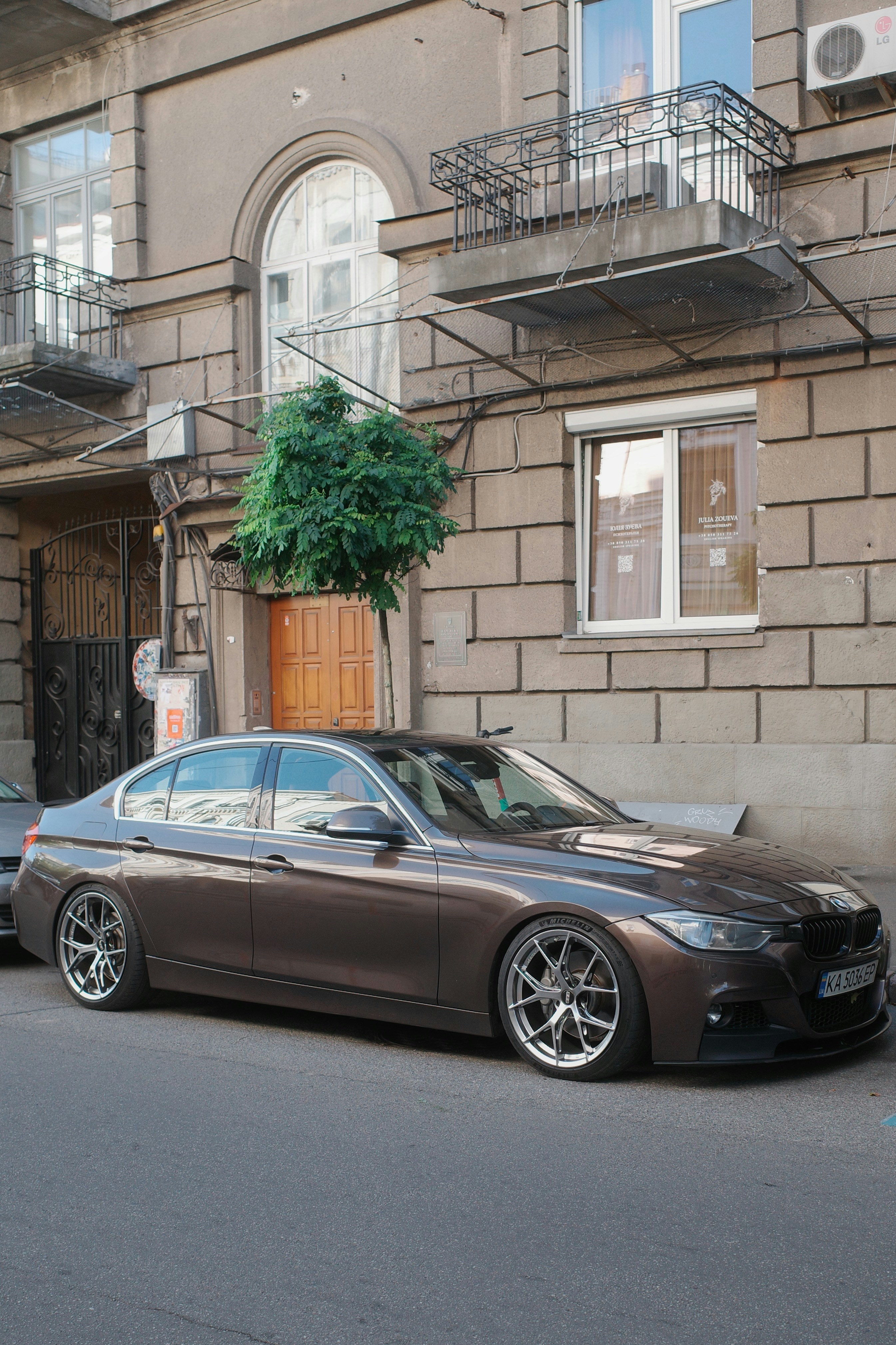 Bronze BMW on a Quiet City Block Under Historic Brick Facades