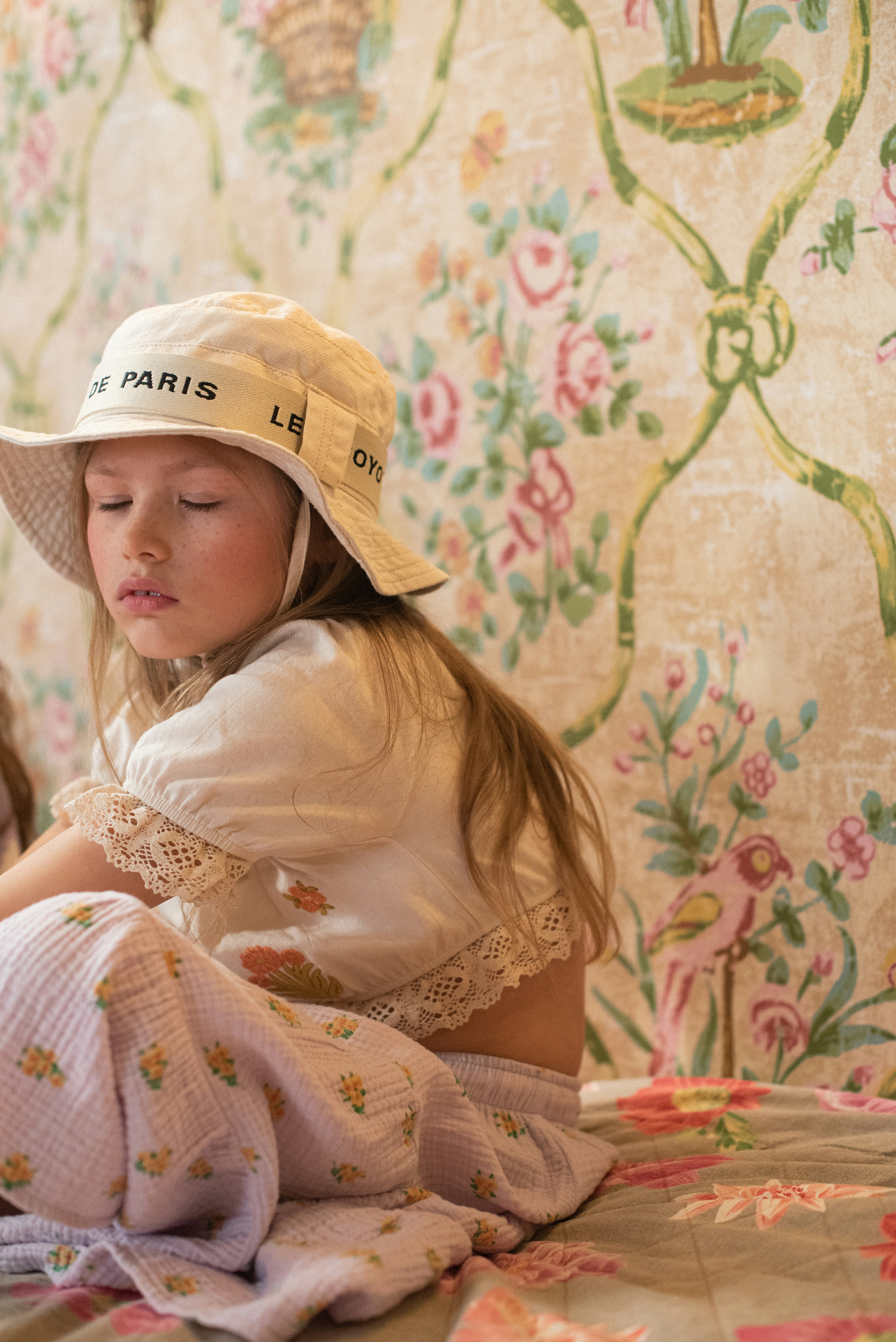  quiet moment under a pastel tapestry: a girl in a sunhat