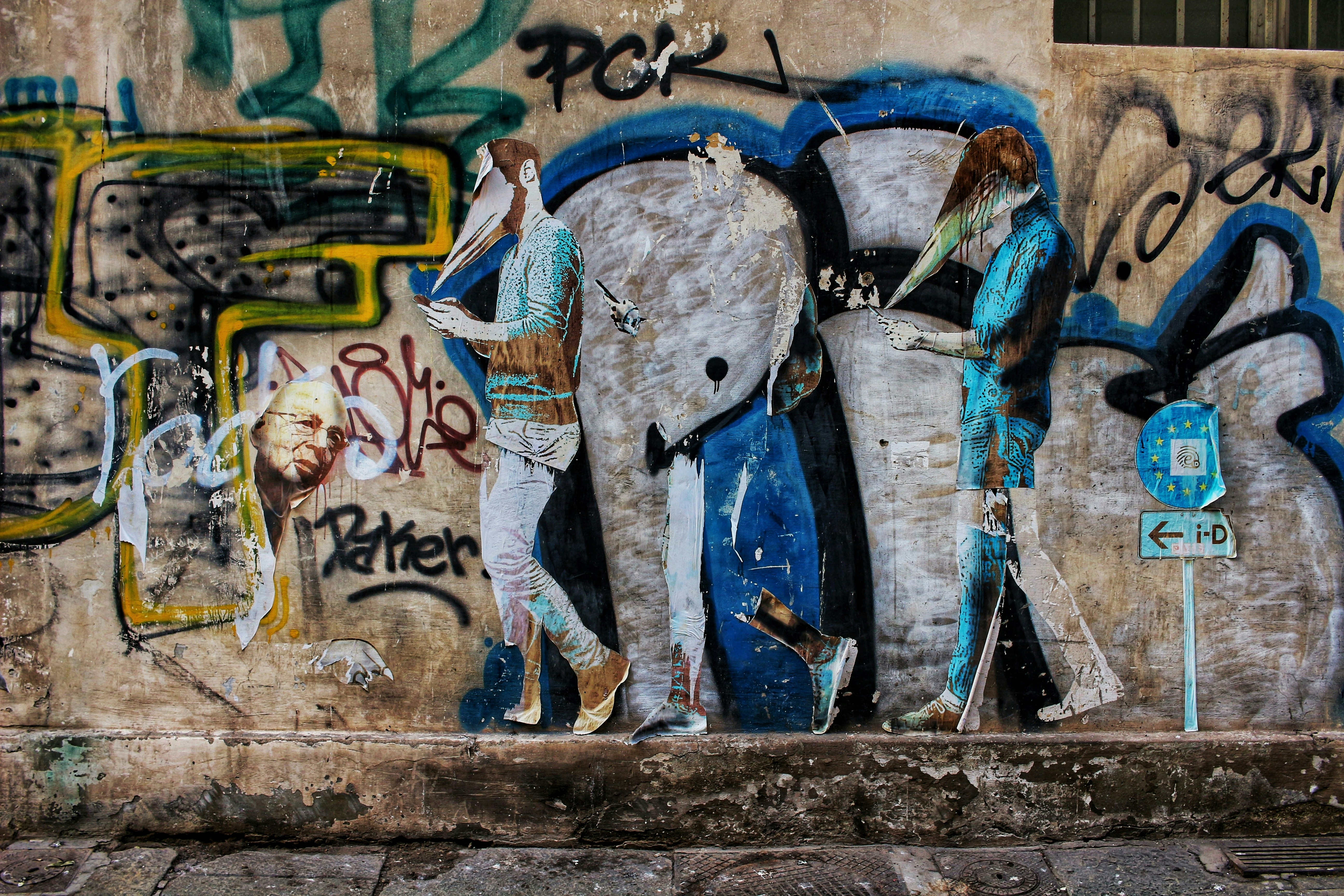 Blue-clad silhouettes stride past a graffiti-drenched urban mural