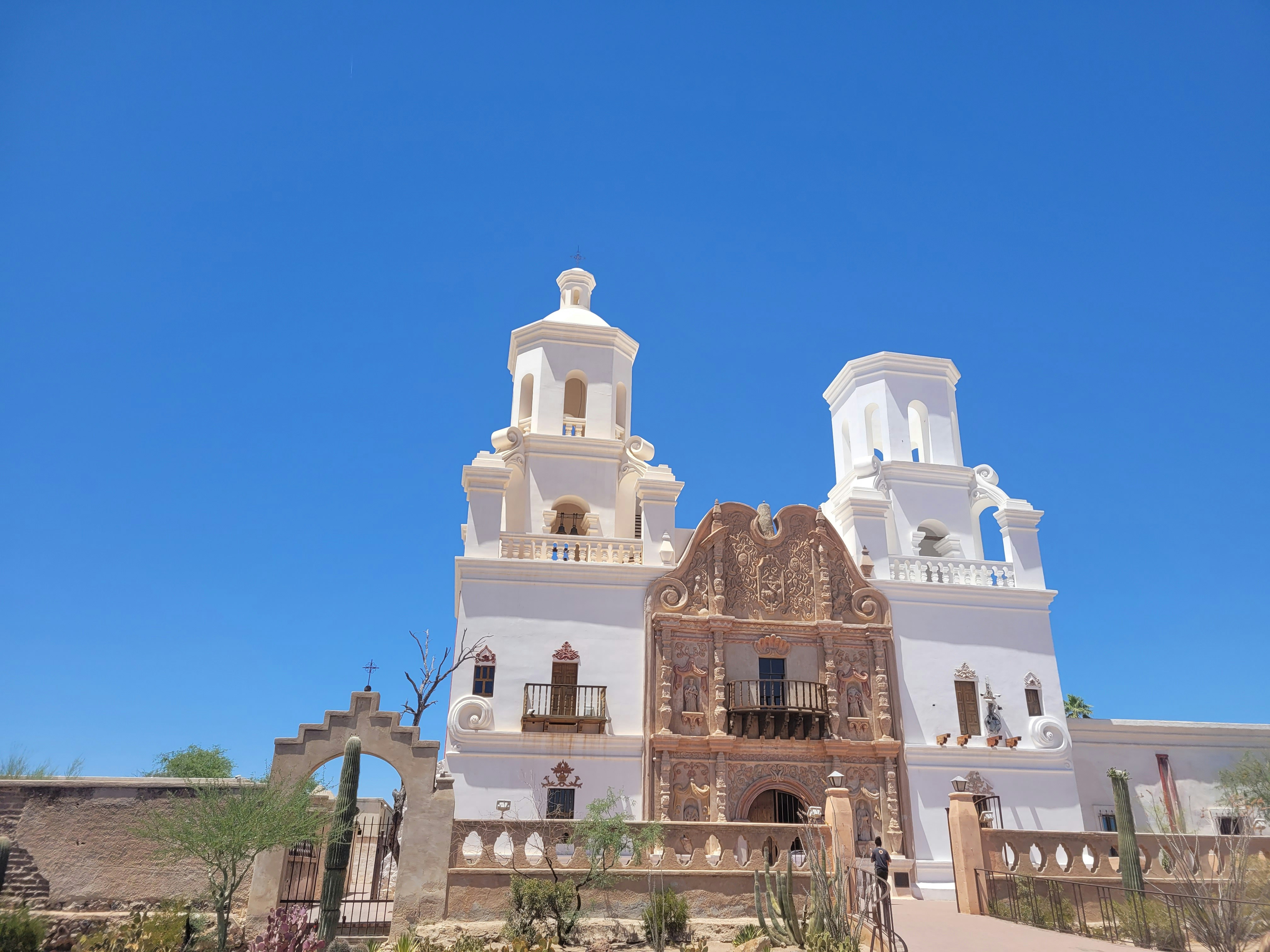 Historic mission church with white towers and ornate facade against a vibrant blue sky.