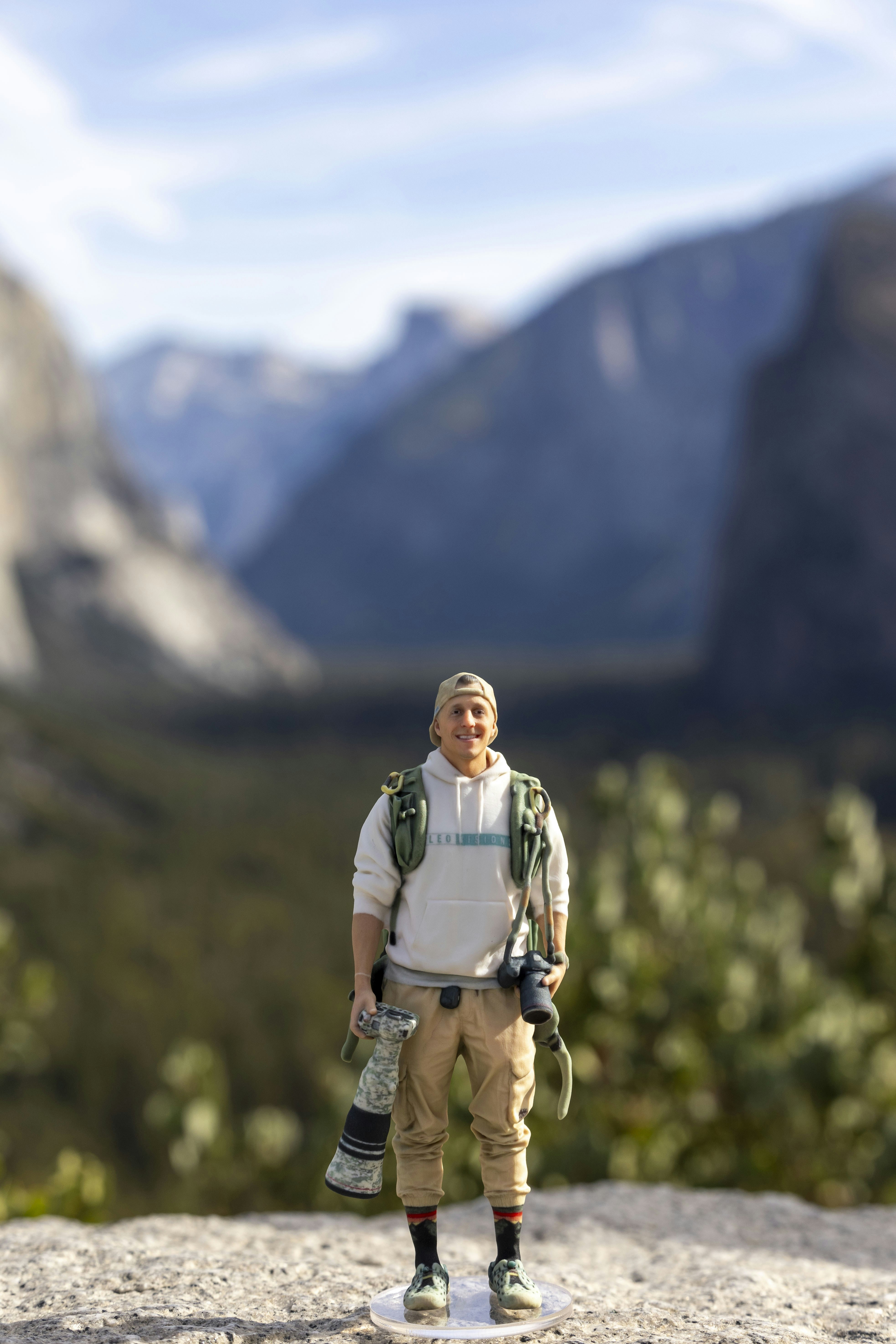 A man with a backpack and camera standing on a rock