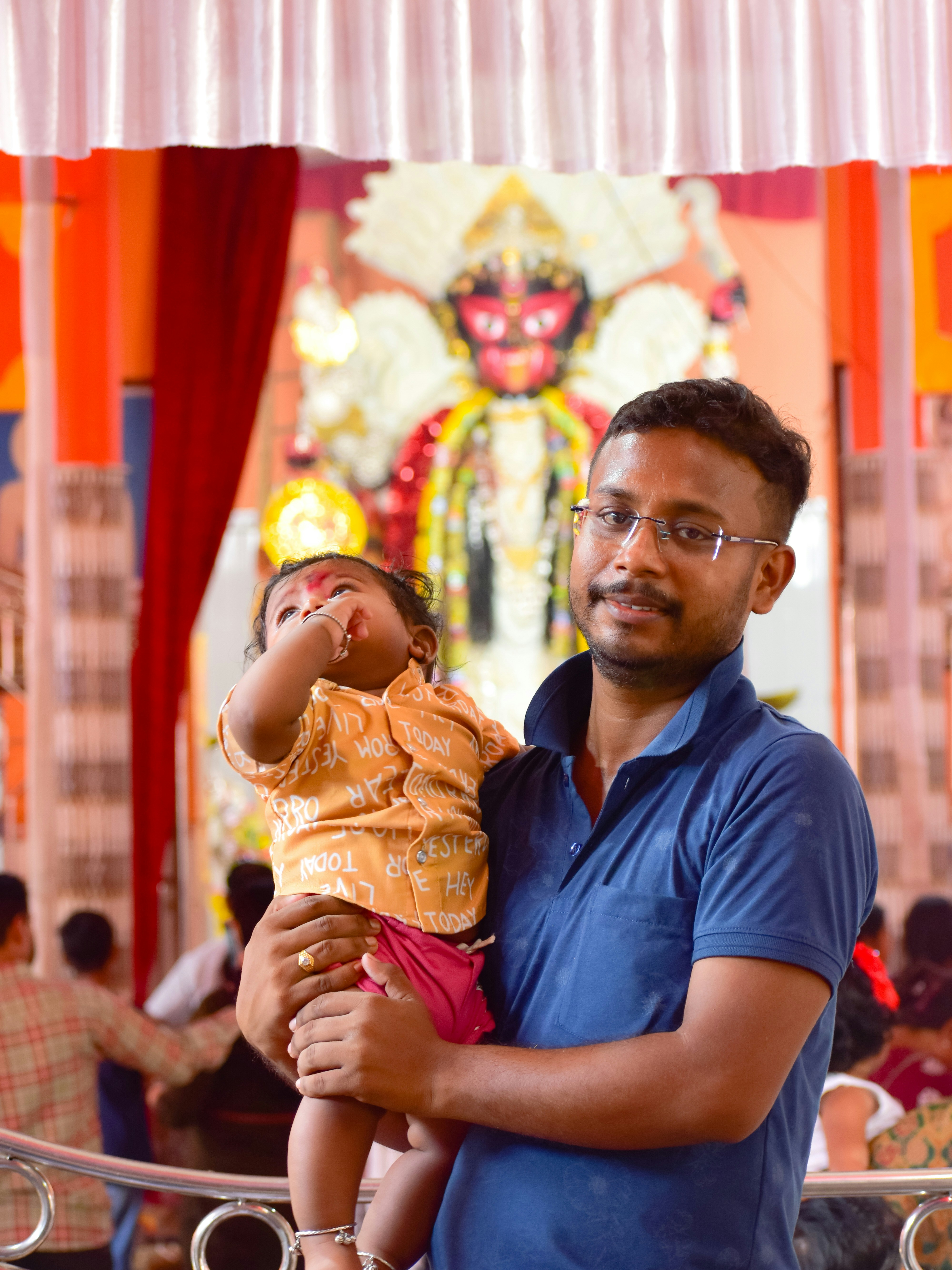 Templelight: A Father's Hold Amid Vibrant Ritual Color