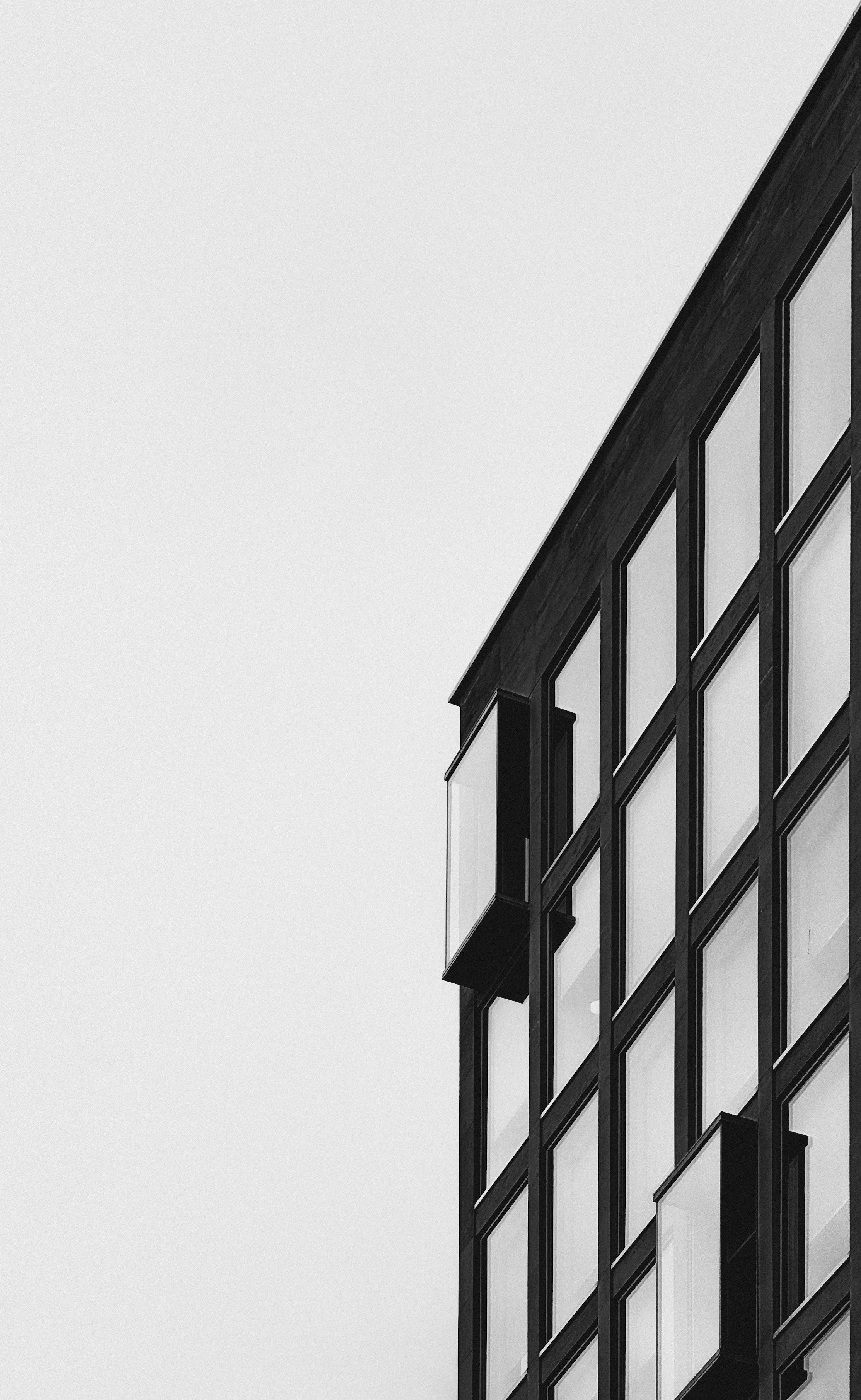 Modern building corner against an overcast sky with sleek, linear architecture and repetitive window patterns.
