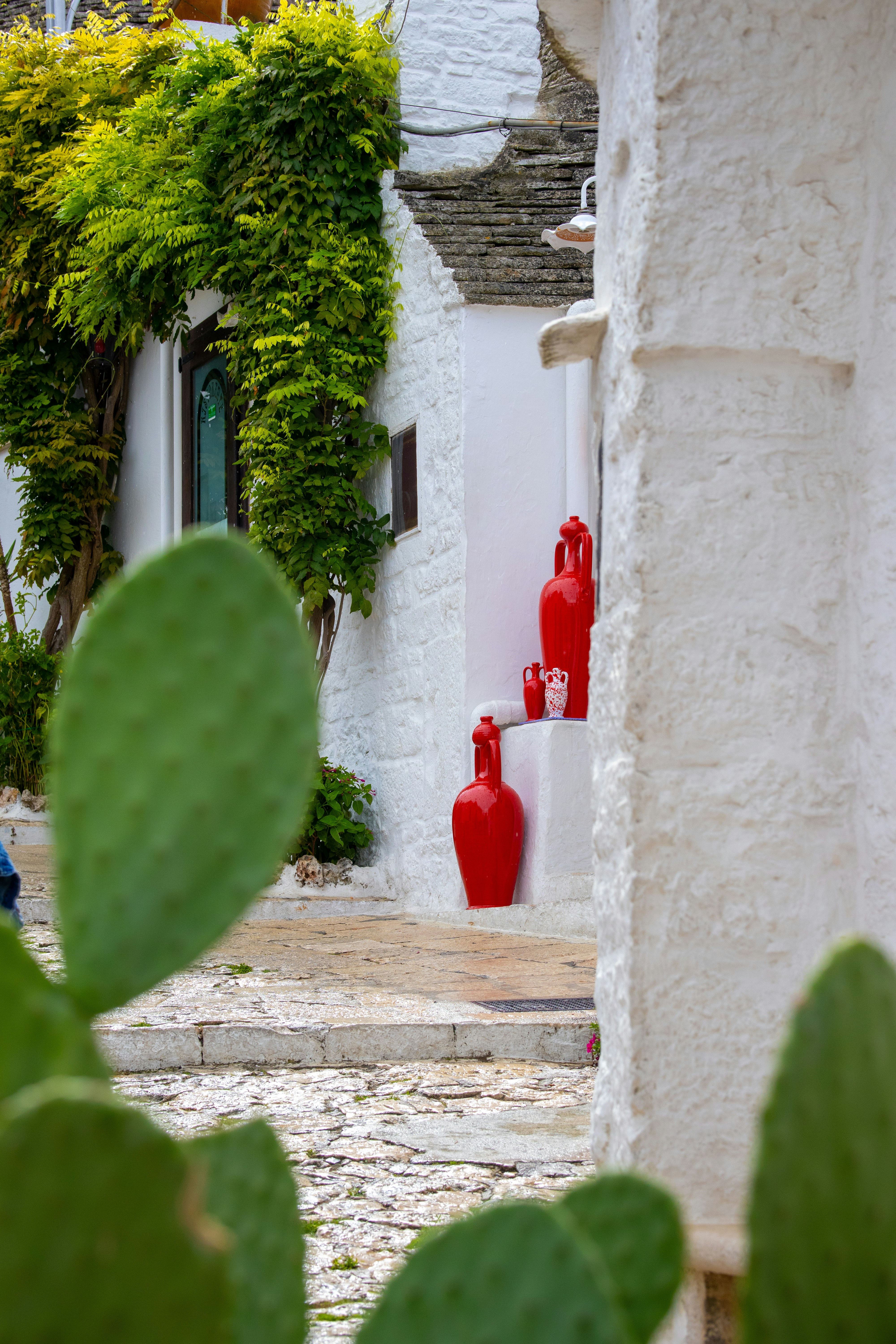 Crimson Vessels Glow Along a Sunlit White Staircase in a Mediterranean Courtyard