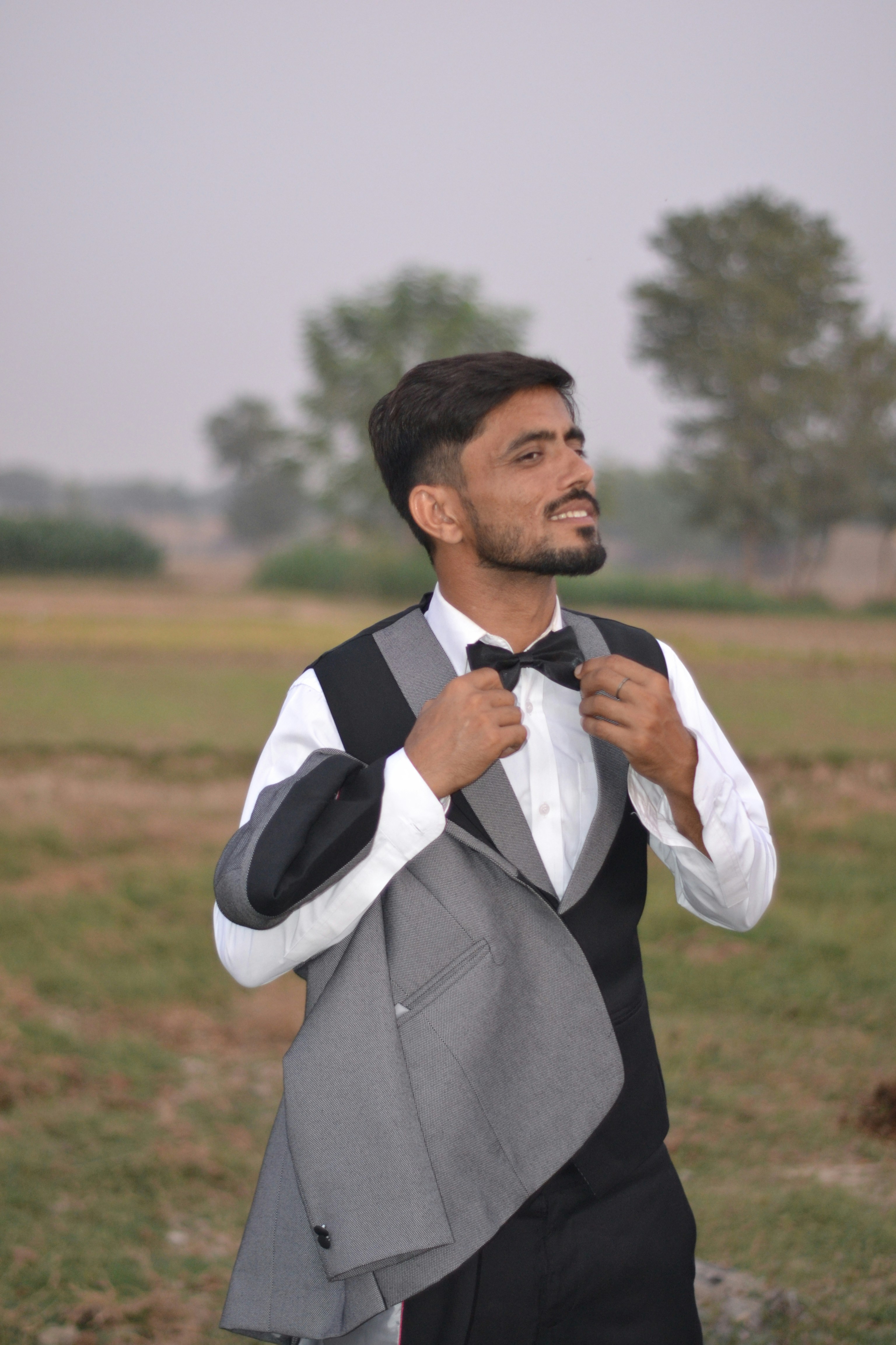 Groom-to-be Adjusting a Bow Tie in an Expansive Rural Field