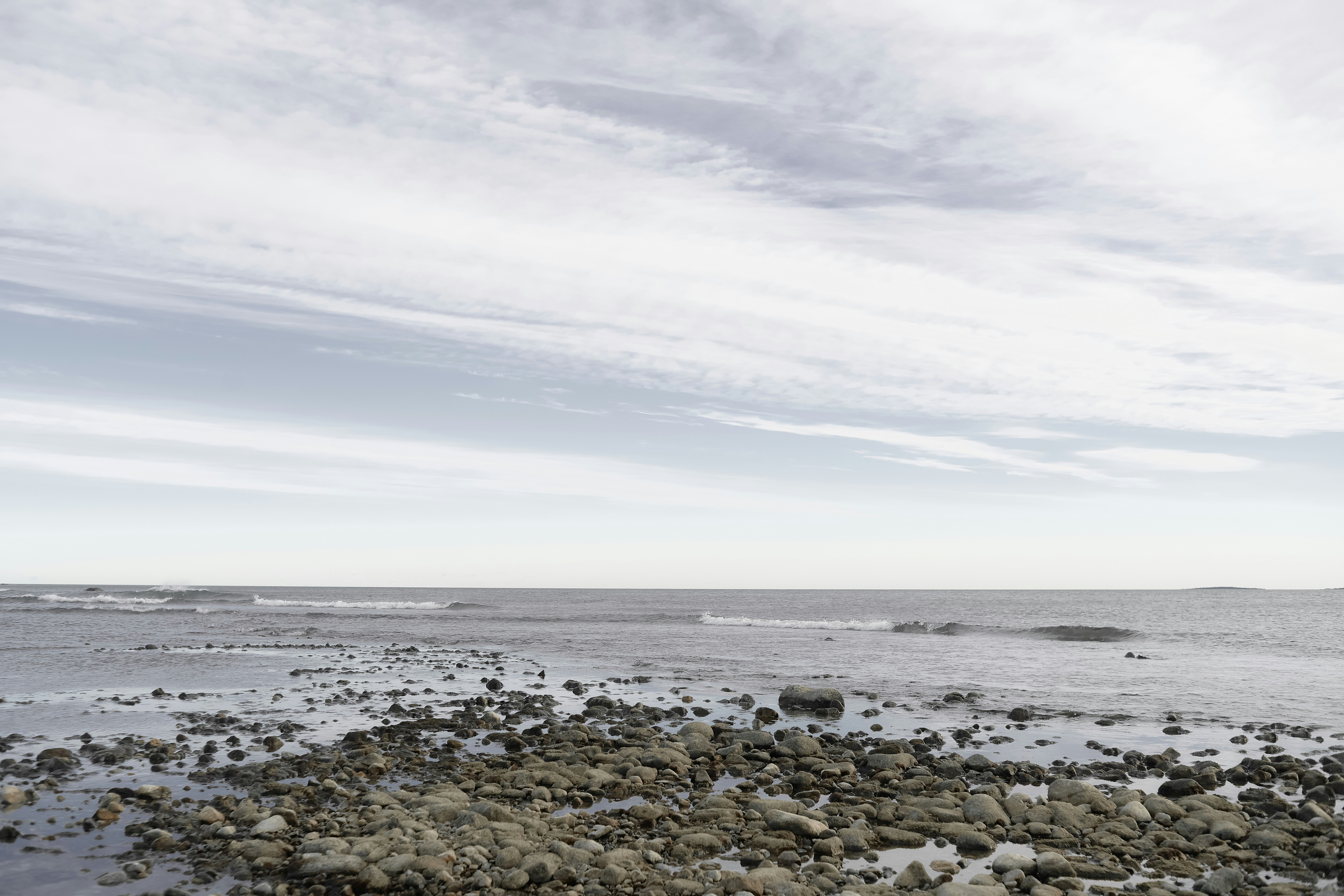 A person standing on a rocky beach next to the ocean photo – Free Karskärs badplats Image on ...