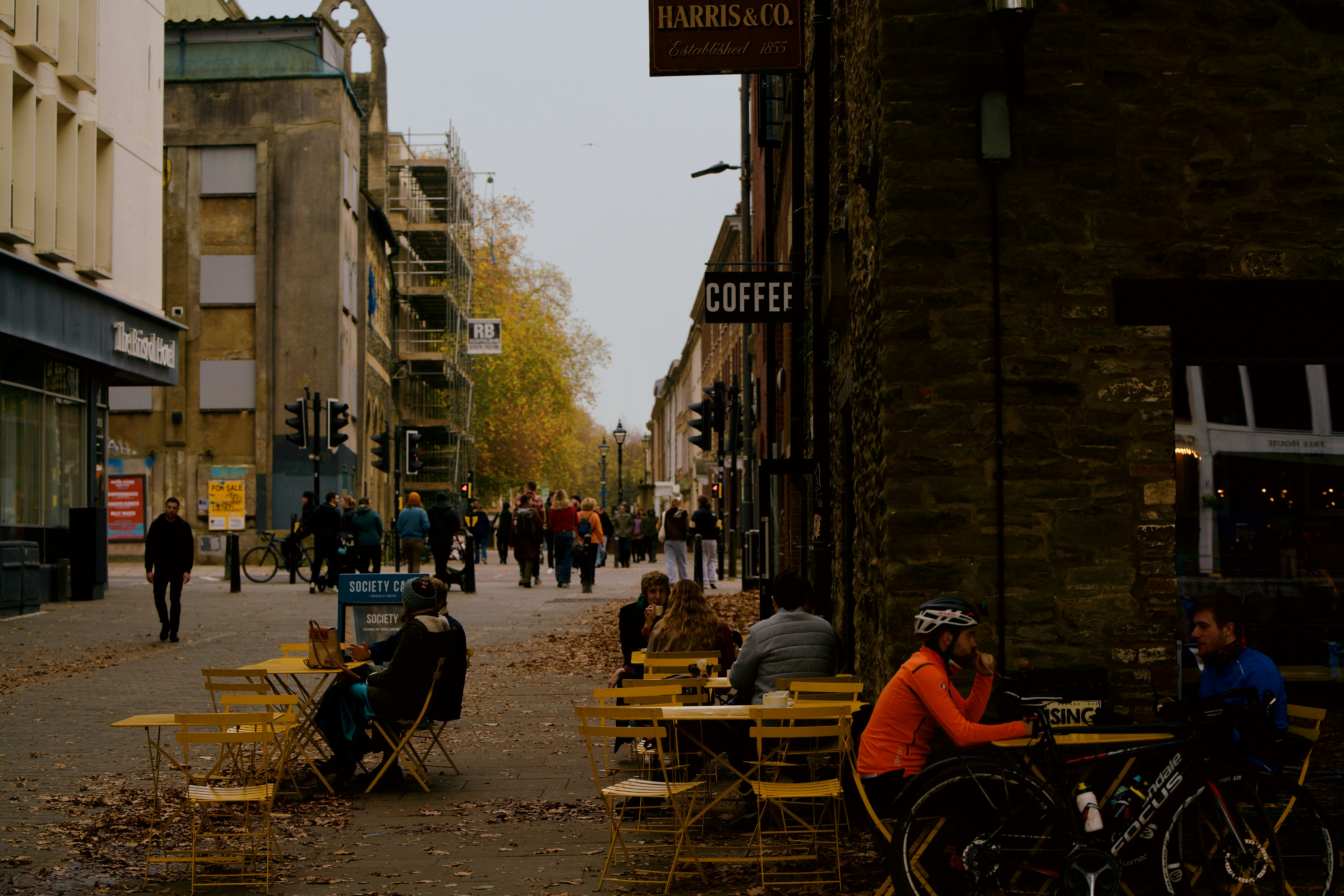 Autumn Street Café: Sunlit Yellow Tables Along a Quiet Pedestrian Lane