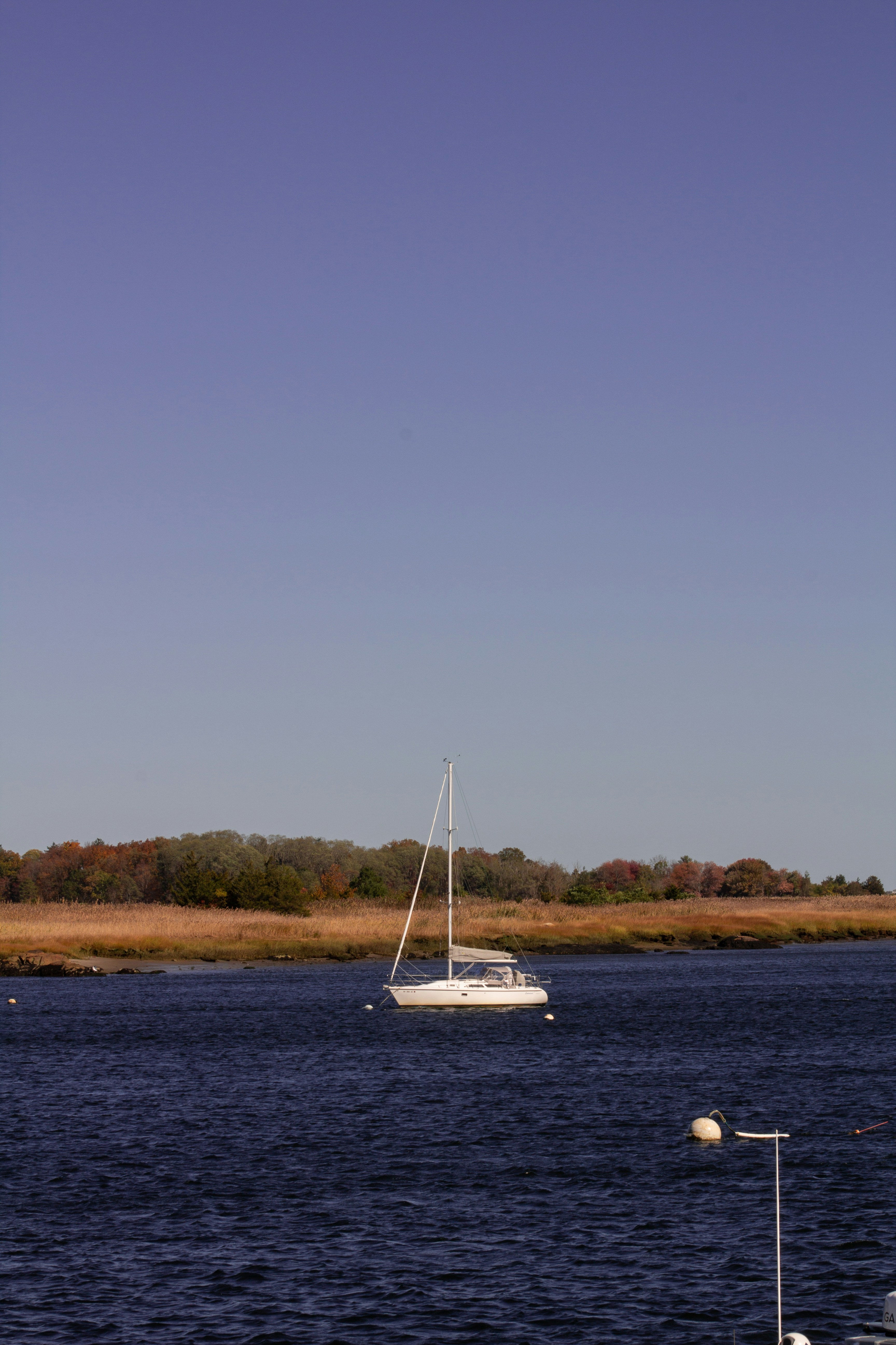 Autumn Quiet: A Lone Sailboat on a Wide River Under a Gradient Sky