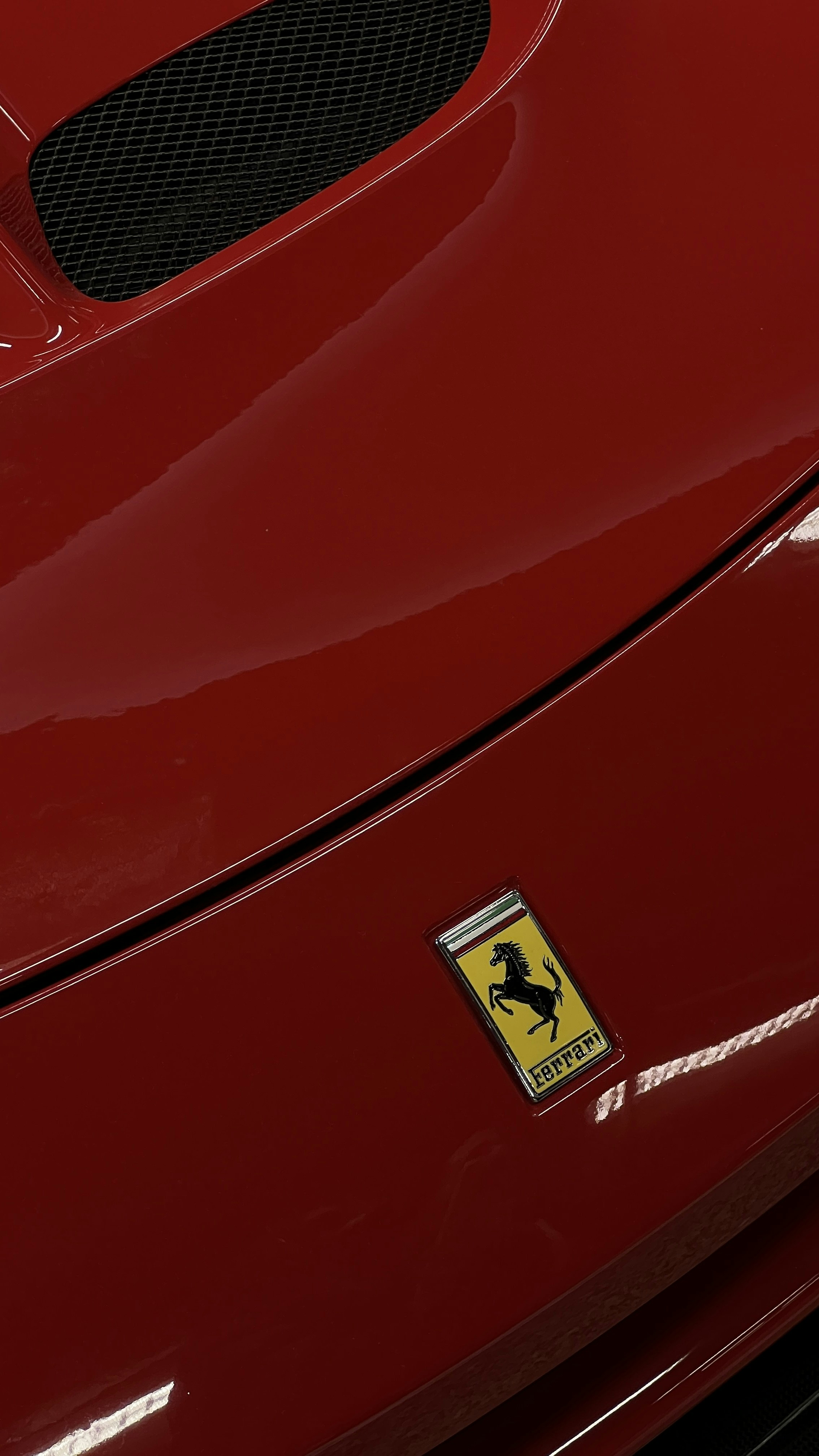 Crimson Crest: Ferrari Emblem on a Glossy Red Hood