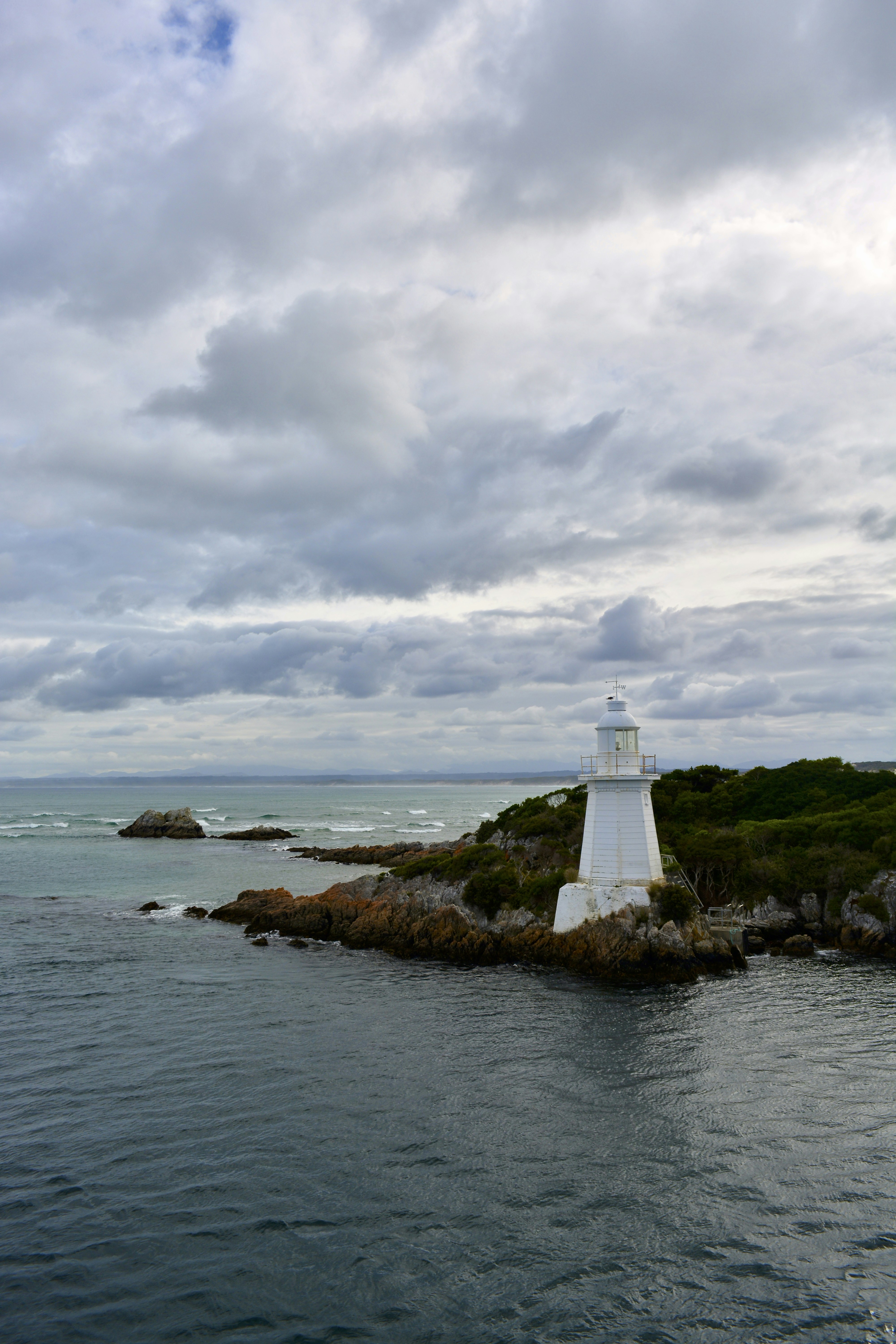 A lighthouse on an island in the middle of the ocean photo – Free ...