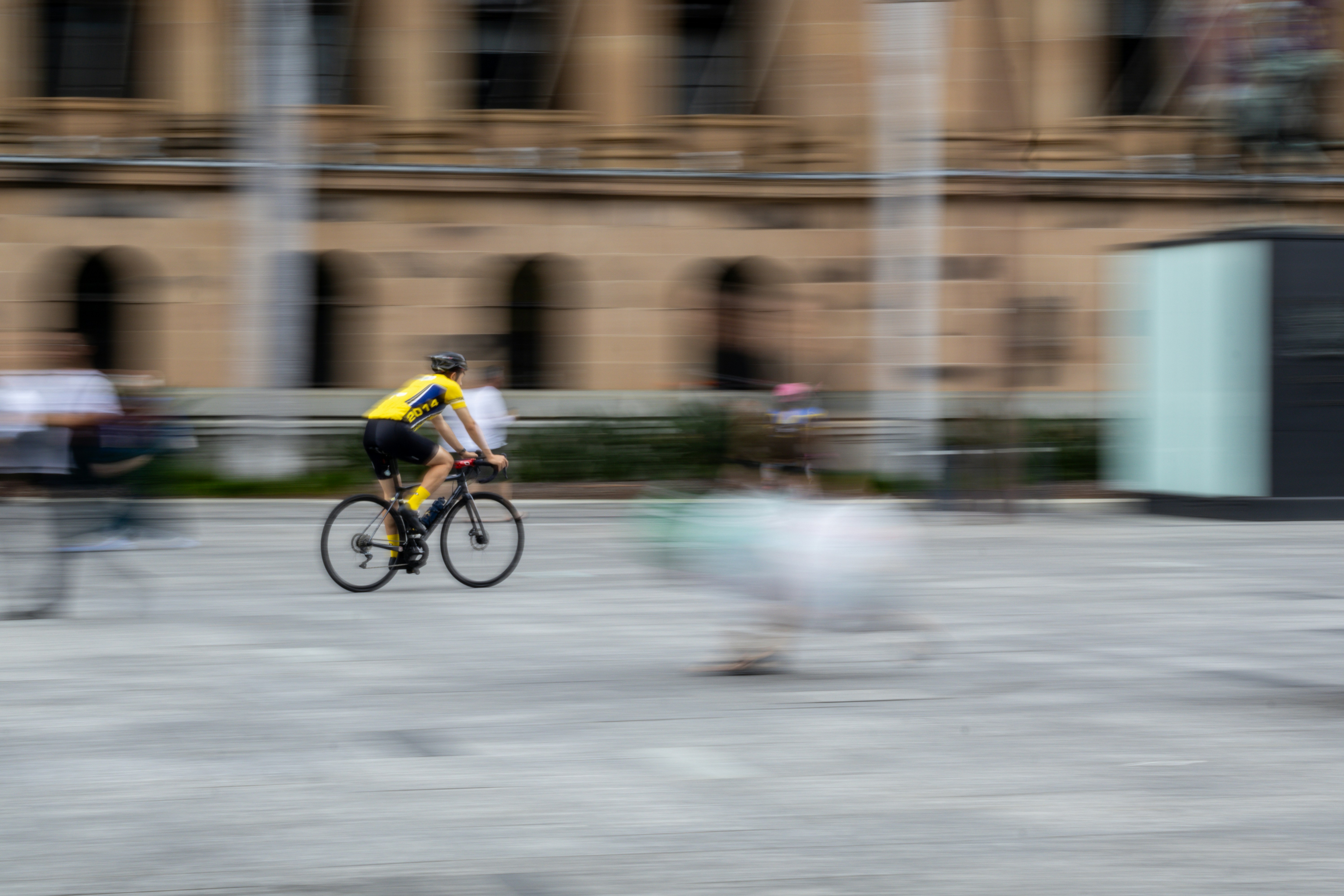 Piazza in Motion: a yellow-clad cyclist slices through a stone plaza