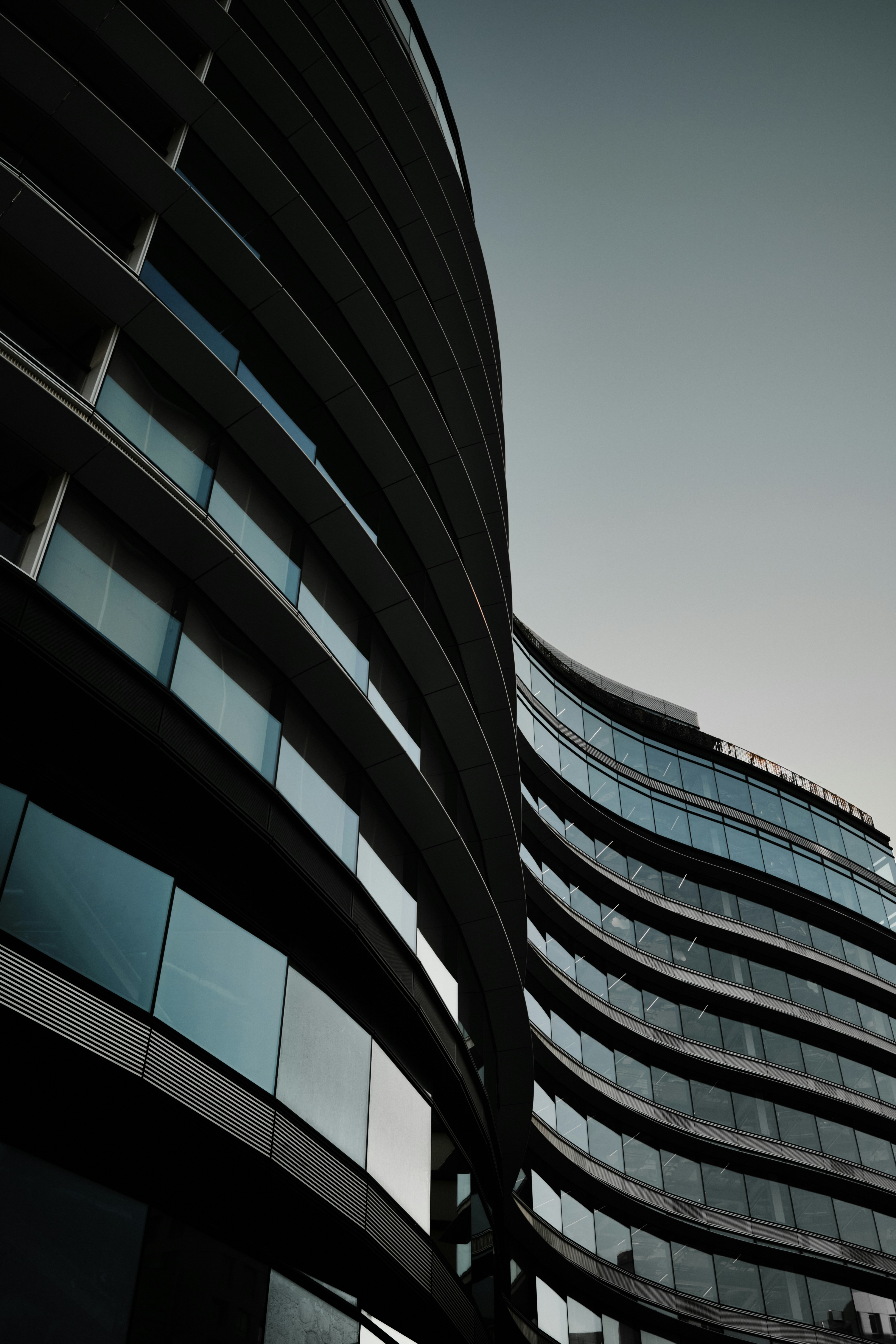 A tall building with many windows next to another building photo – Free ...