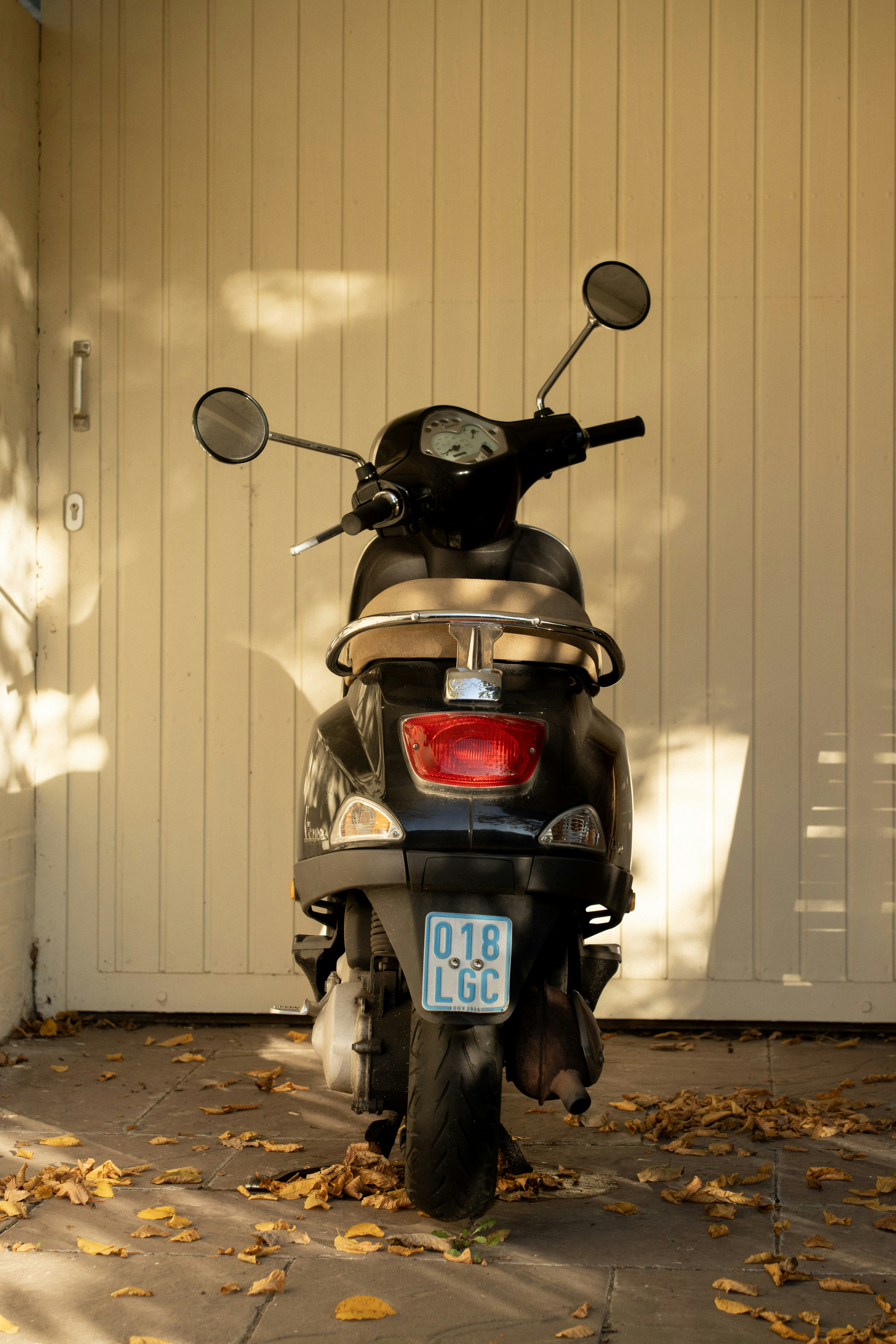 Quiet Street Shadow: Back View of a Scooter Under Autumn Light