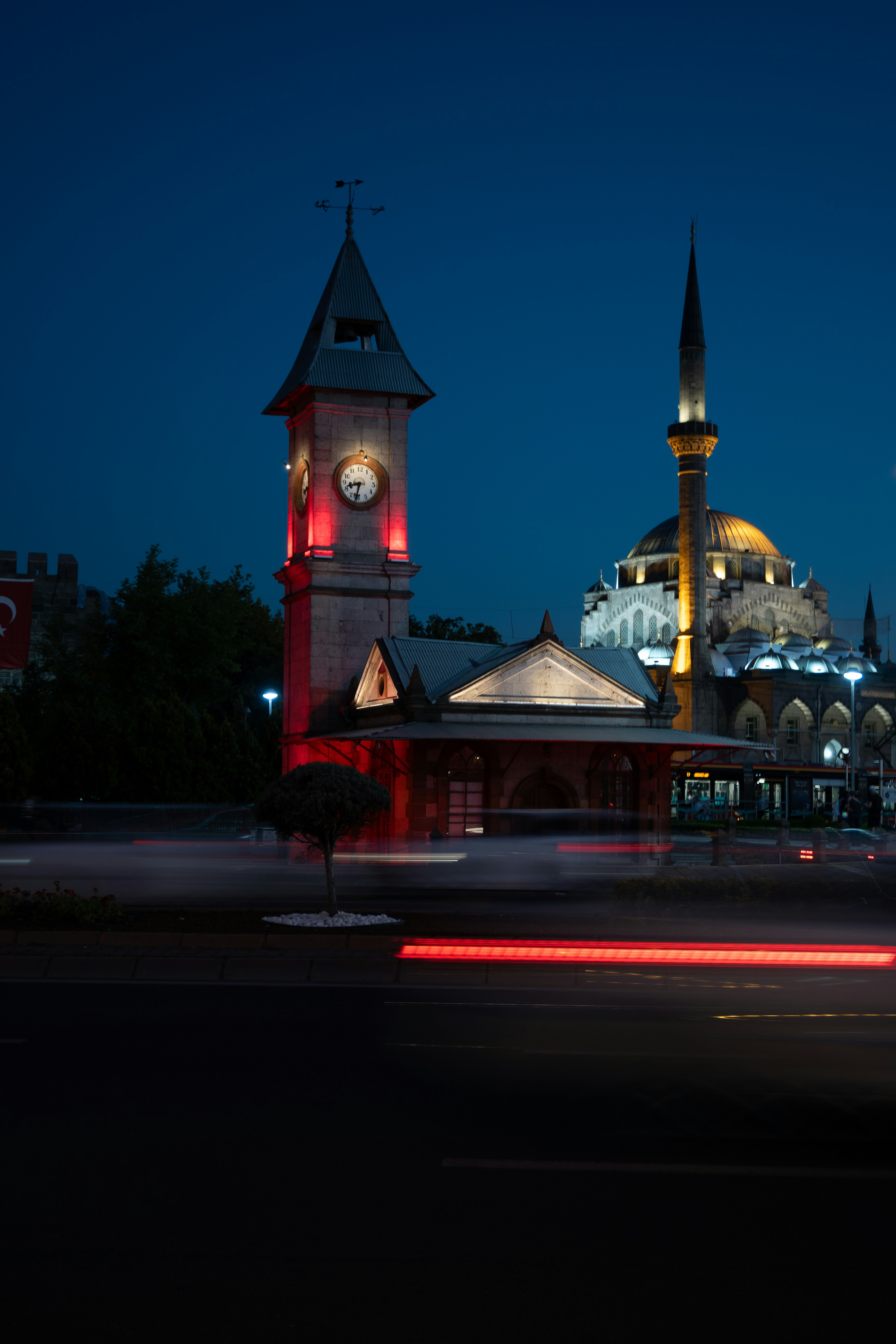 Crimson Clock Tower Illuminates the Night Beside a Domed Mosque