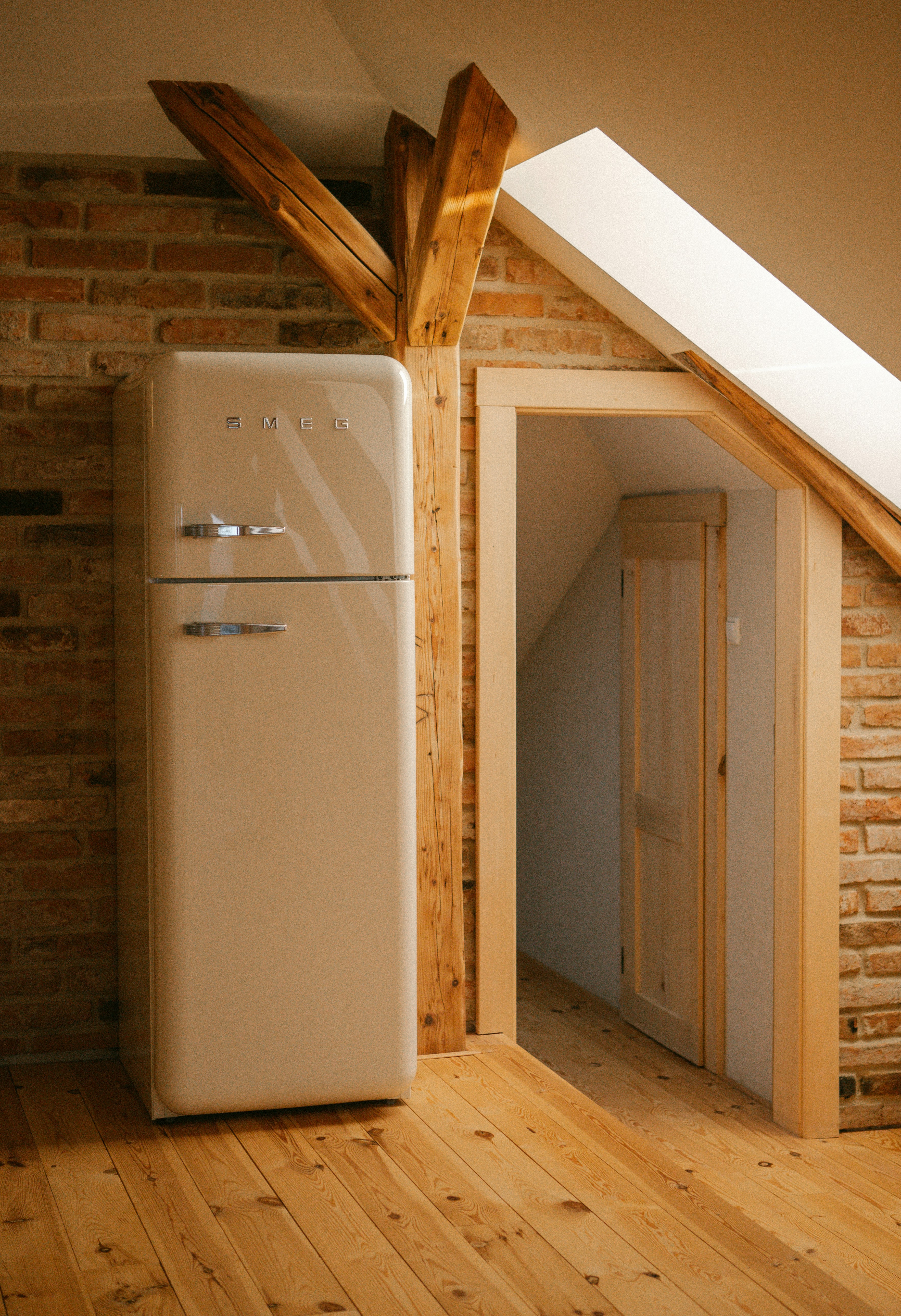 A refrigerator in a room with a slanted roof photo – Free House Image ...