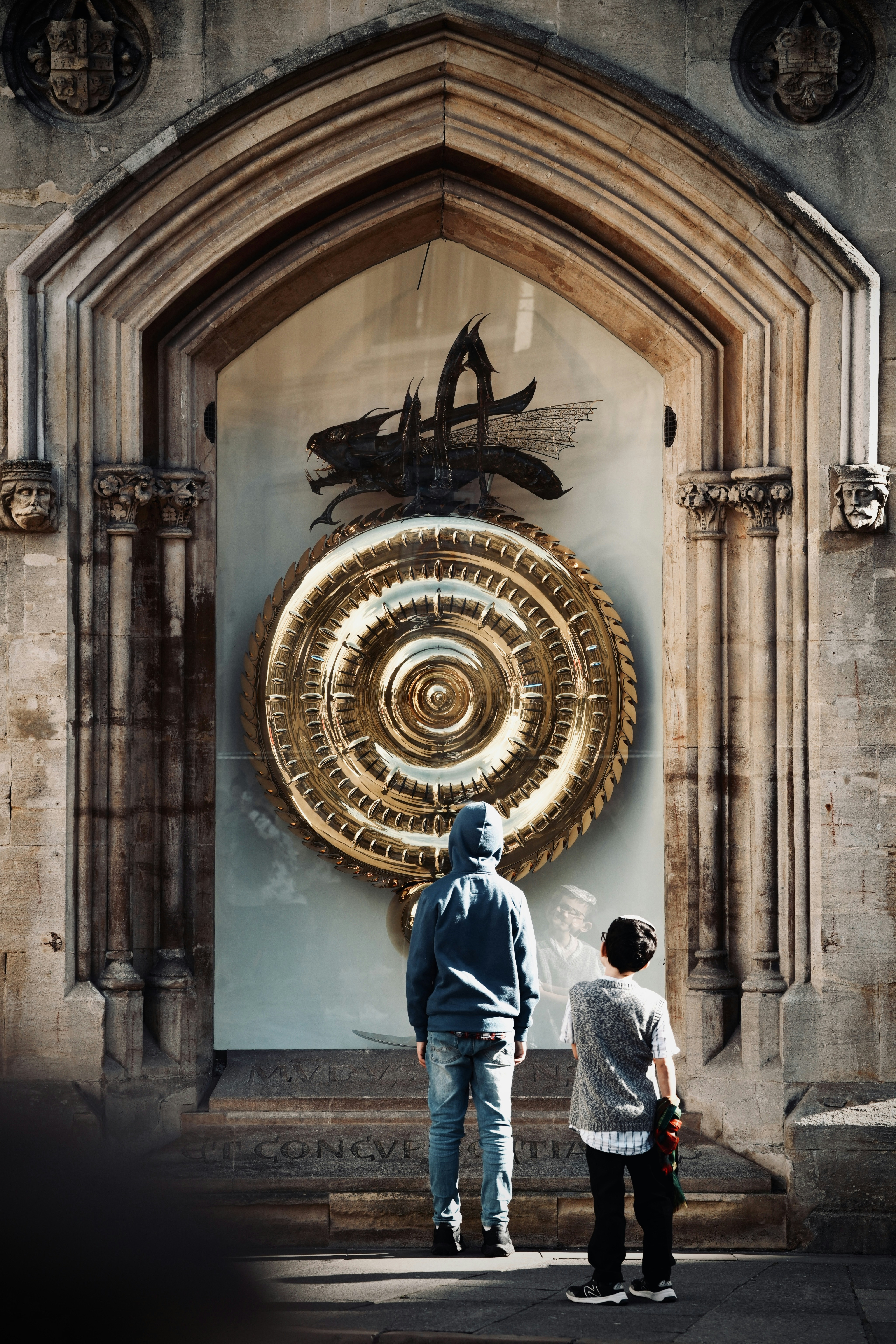 Concentric Gold: Visitors before a colossal ring within a Gothic portal