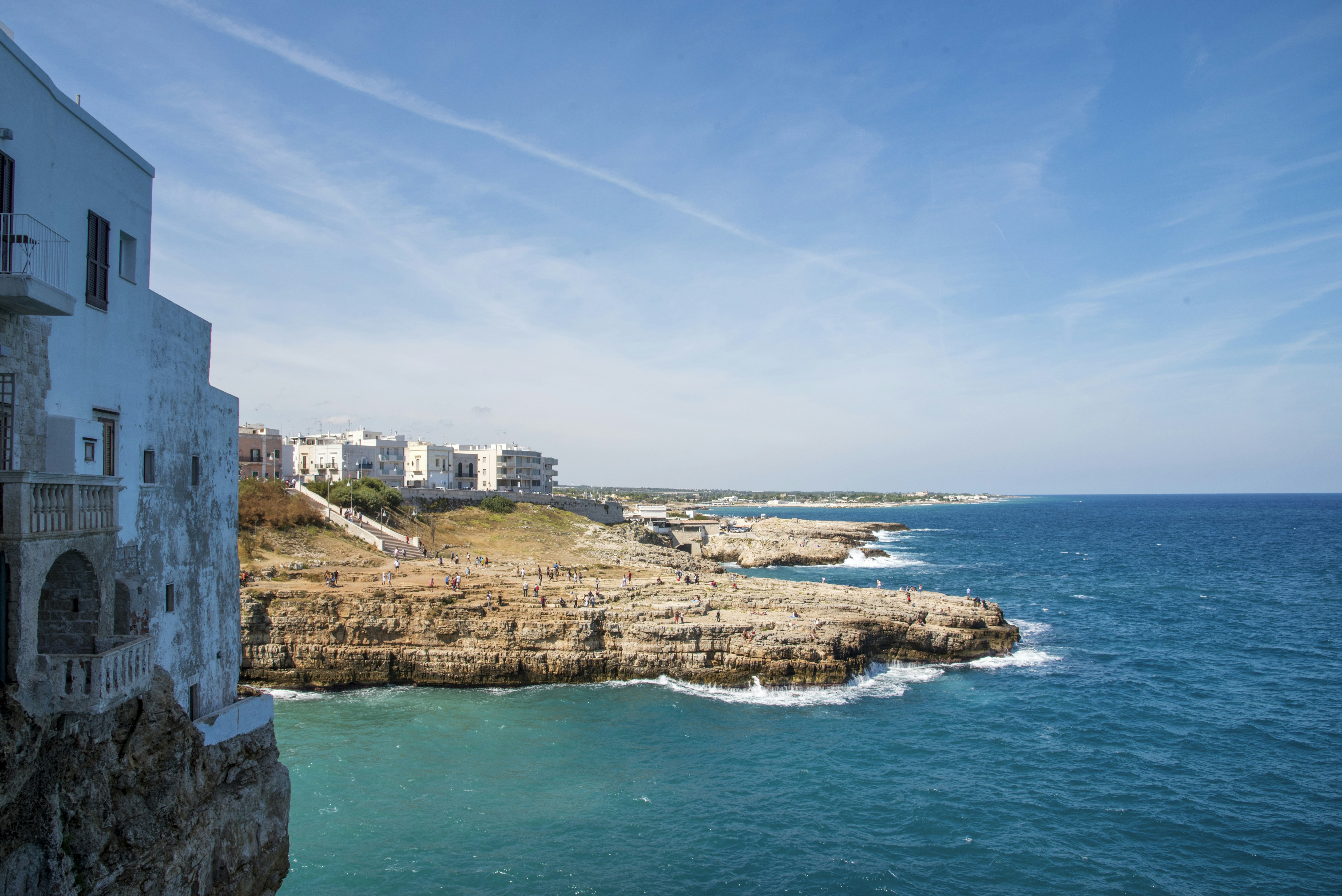 Cliffside buildings overlook the turquoise sea under a clear blue sky.