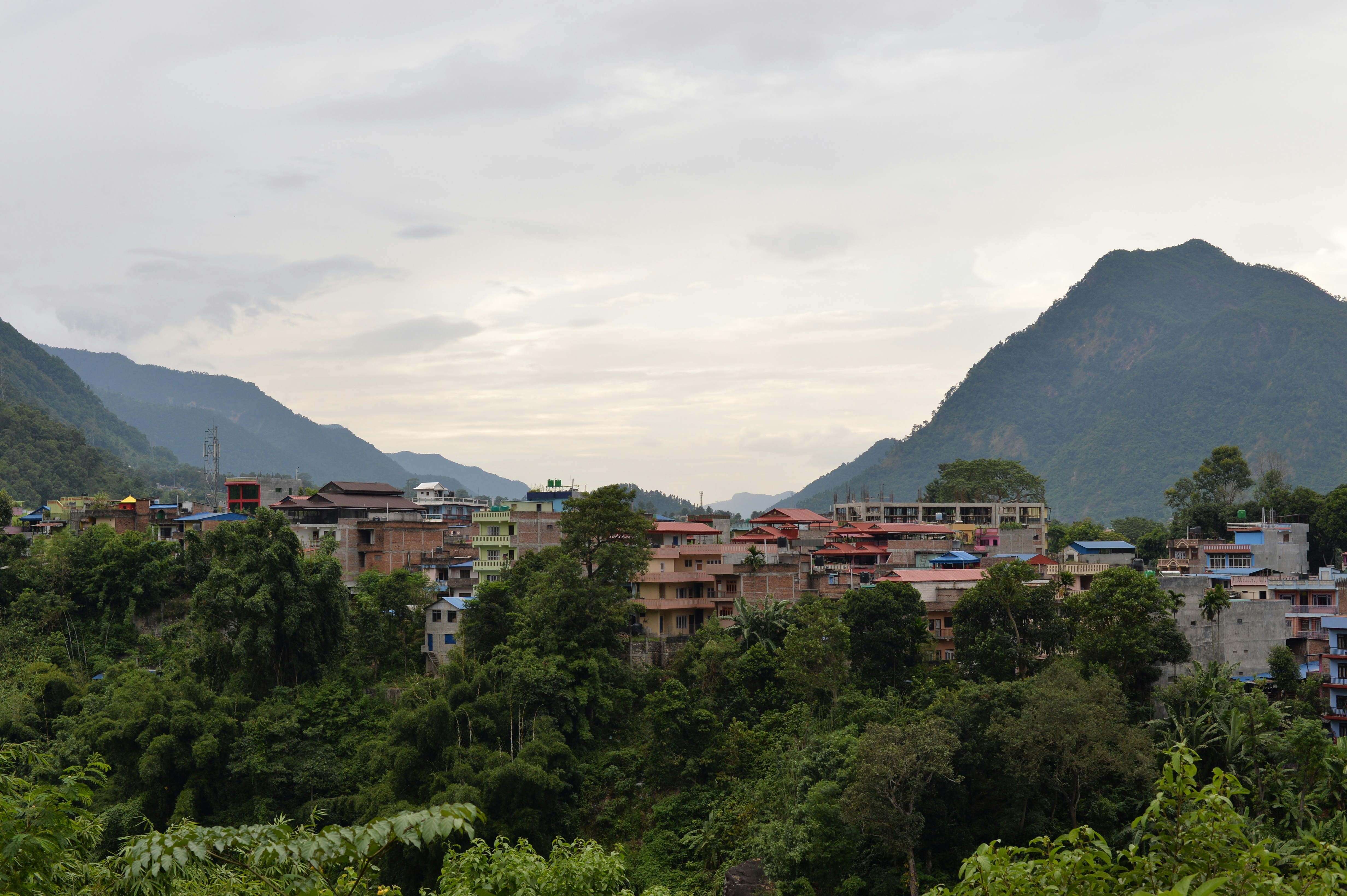 Colorful buildings nestled among lush greenery with mountains in the background, reflecting the coexistence of urban and natural landscapes.