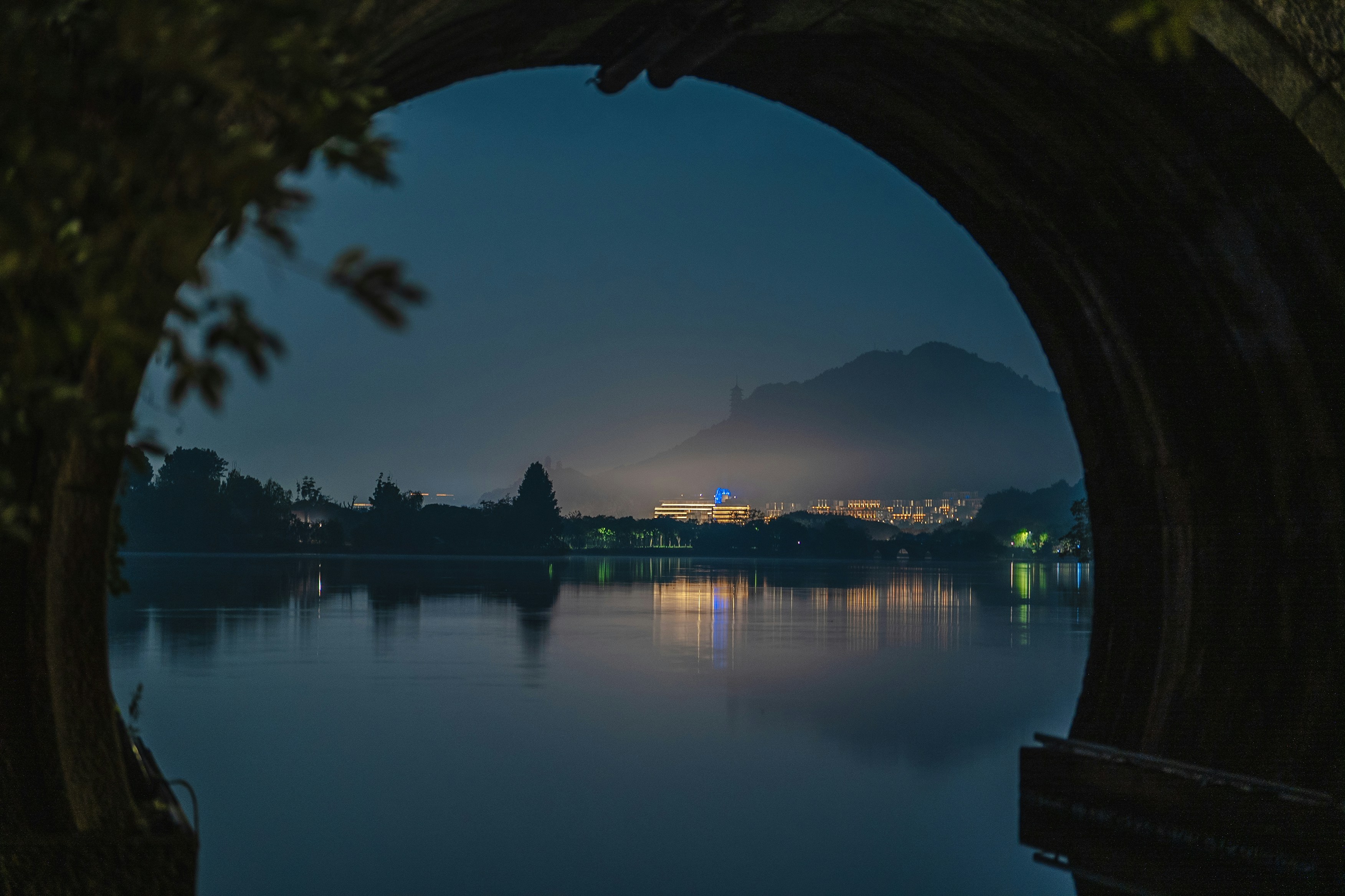 Ring Frame Over the Lake: Night Lights Reflected Beyond a Circular Tunnel