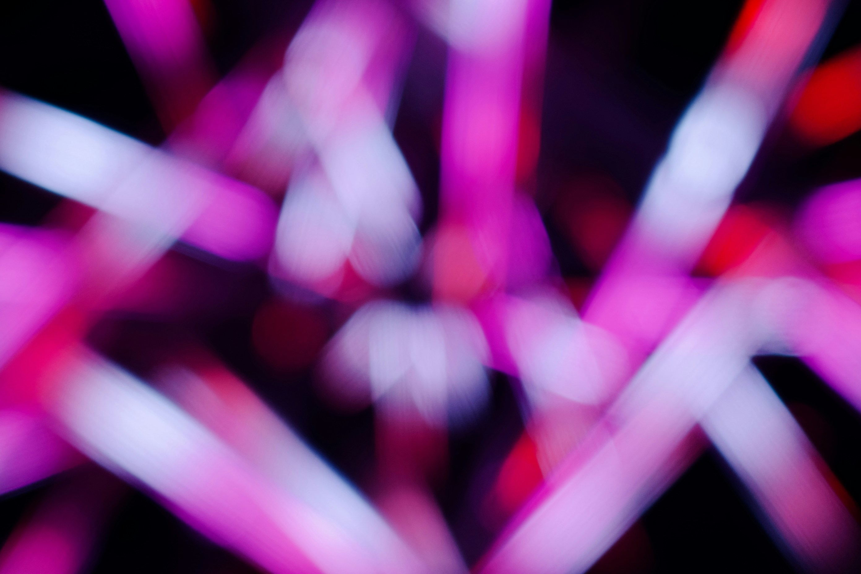 Blurred neon pink and white lights intersecting in a dark background.