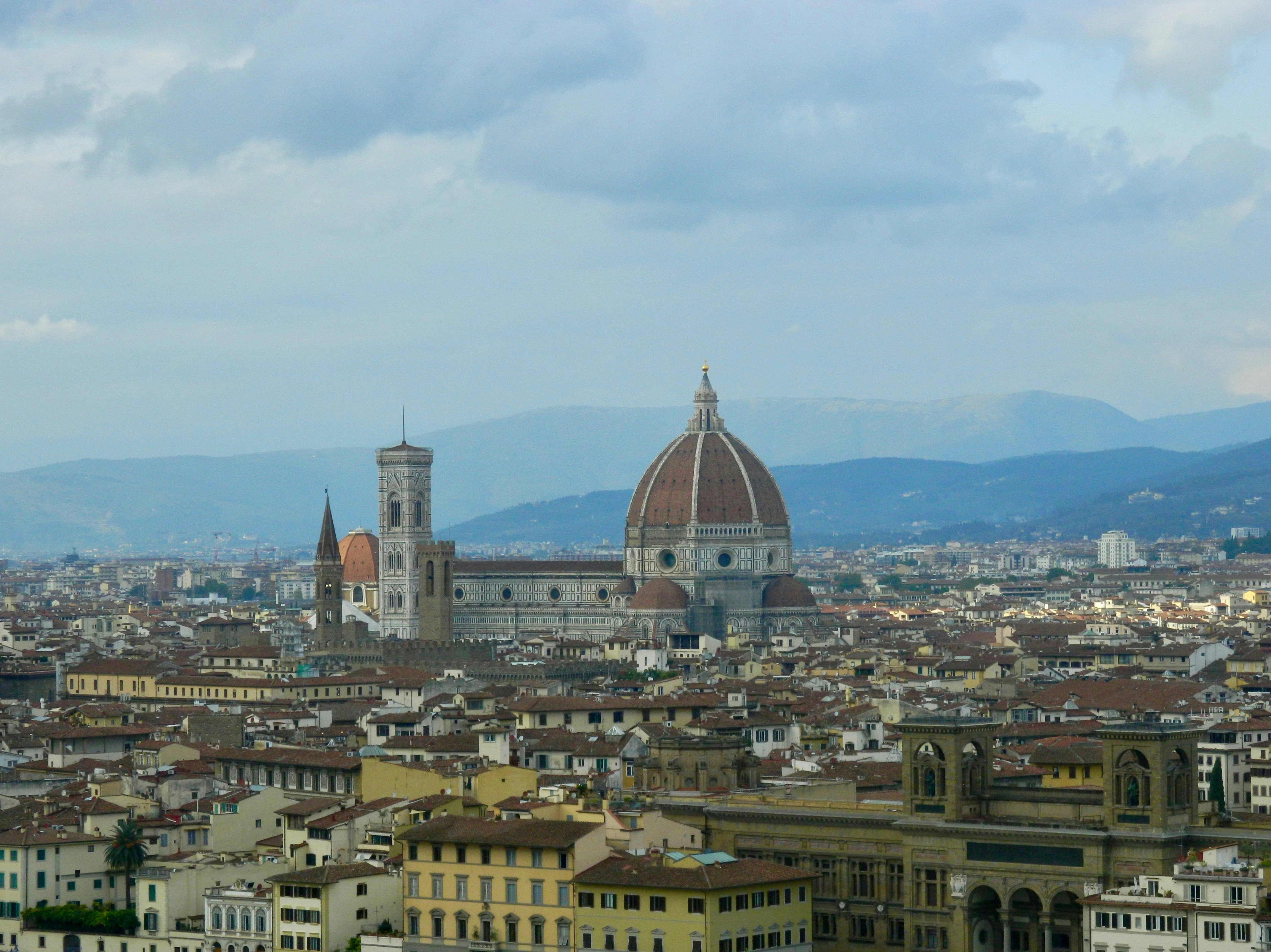 Florence's iconic cathedral stands prominently against a backdrop of rolling mountains and a sprawling cityscape.