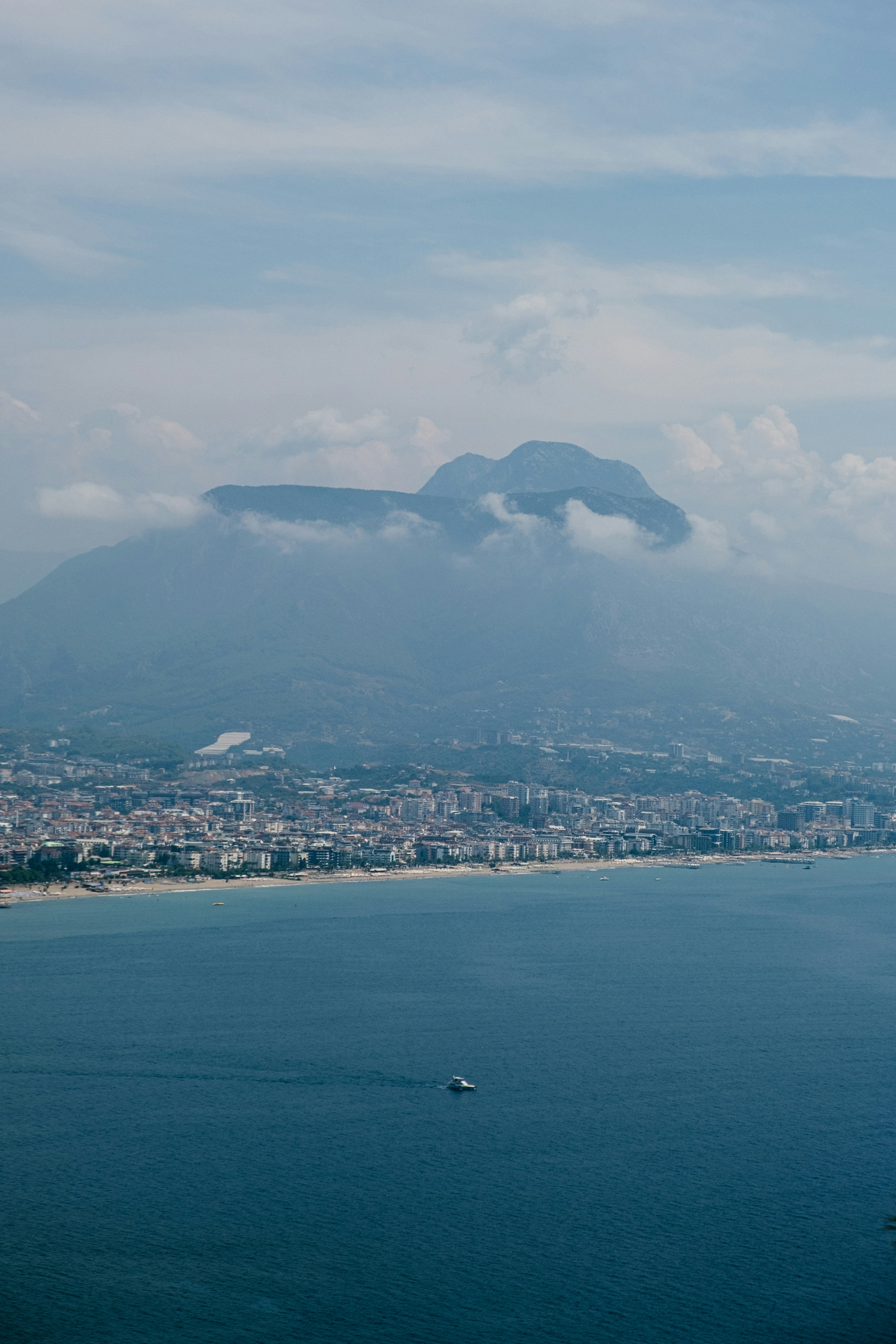 Coastal City at the Foot of a Cloud-Wedged Volcano