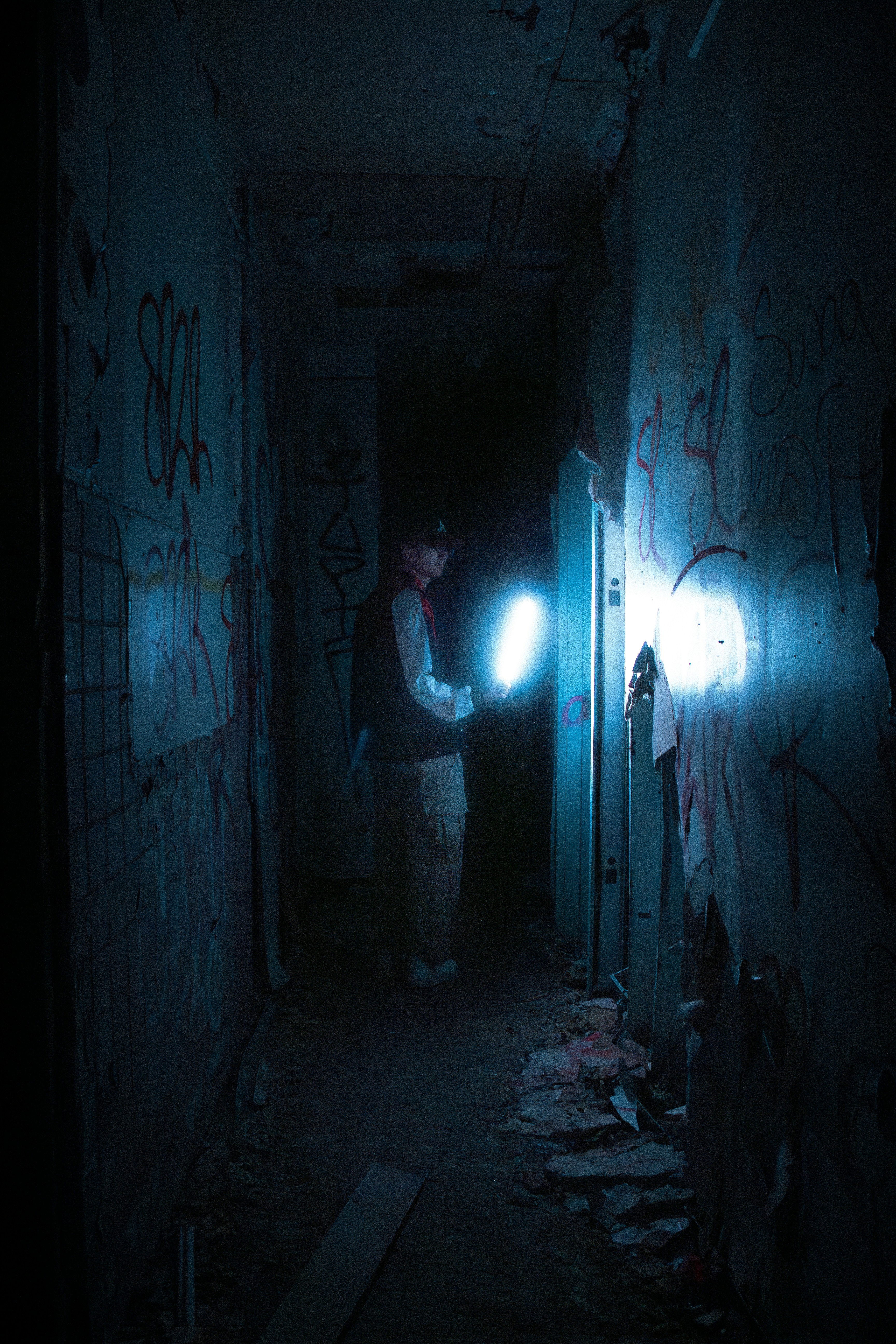 A man standing in a dark hallway holding a flashlight photo – Free ...