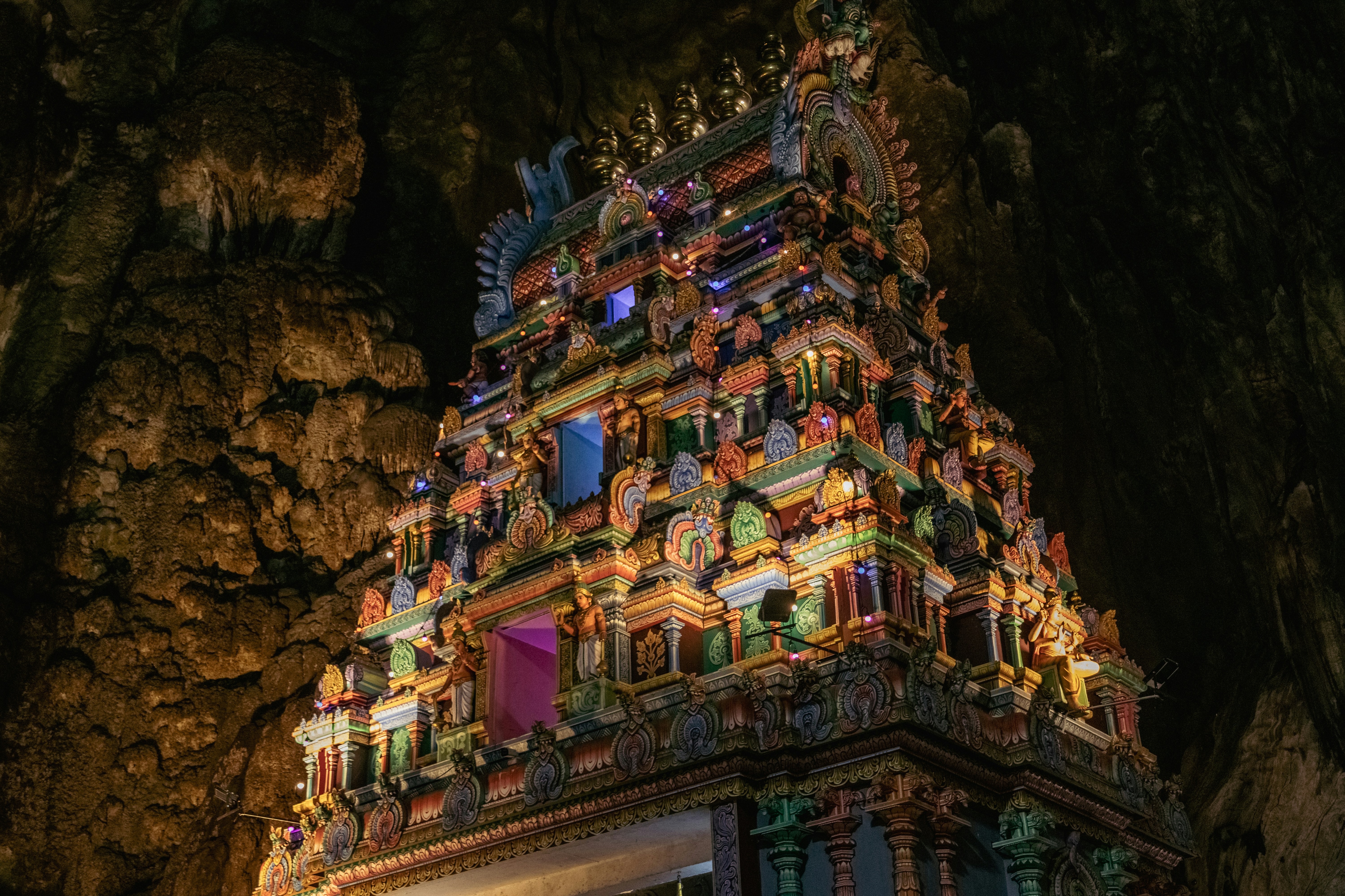 Intricately carved Hindu temple tower brightly lit inside Batu Caves.