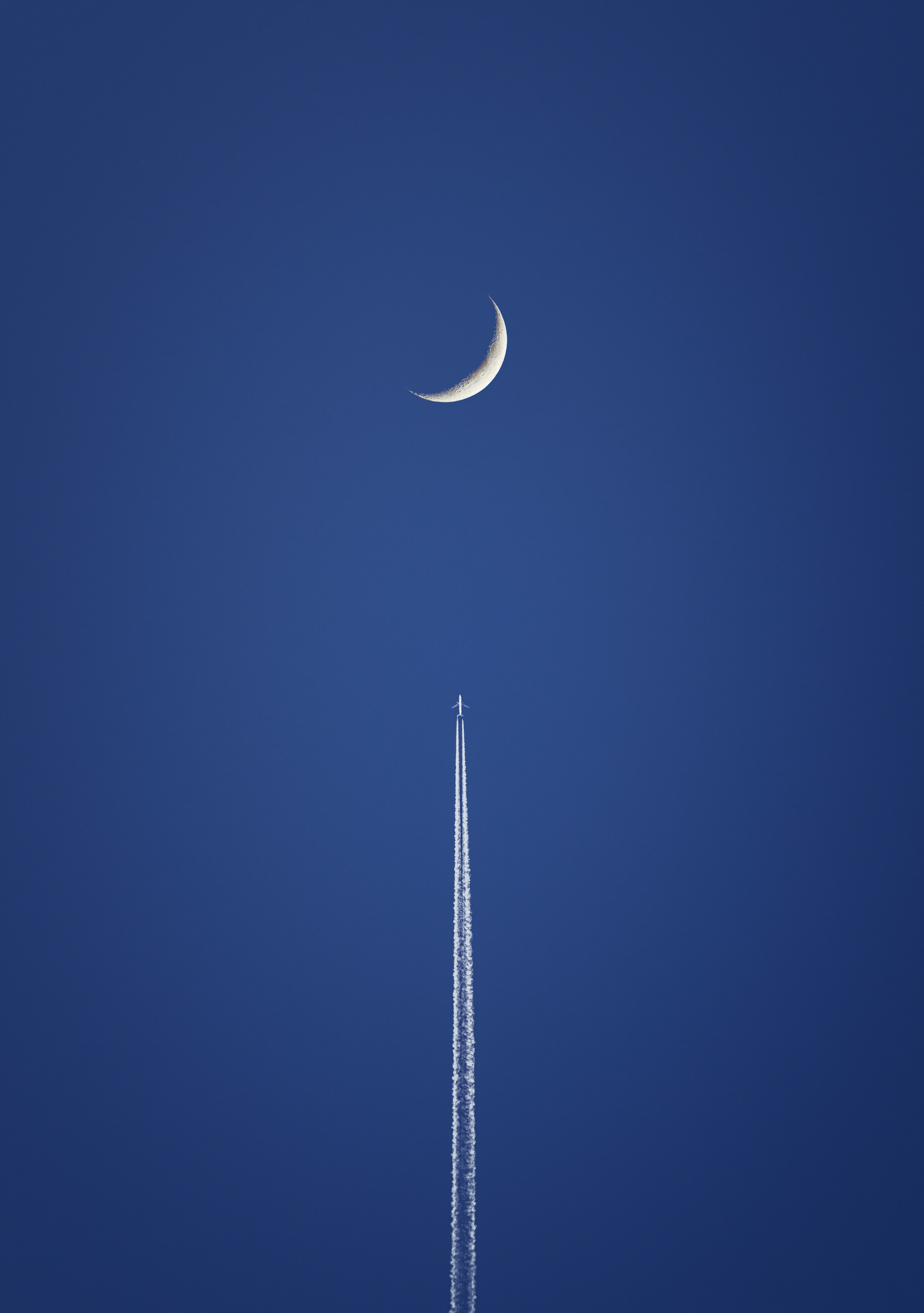 Moonlit Convergence: Jet Trail Beneath a Sliver