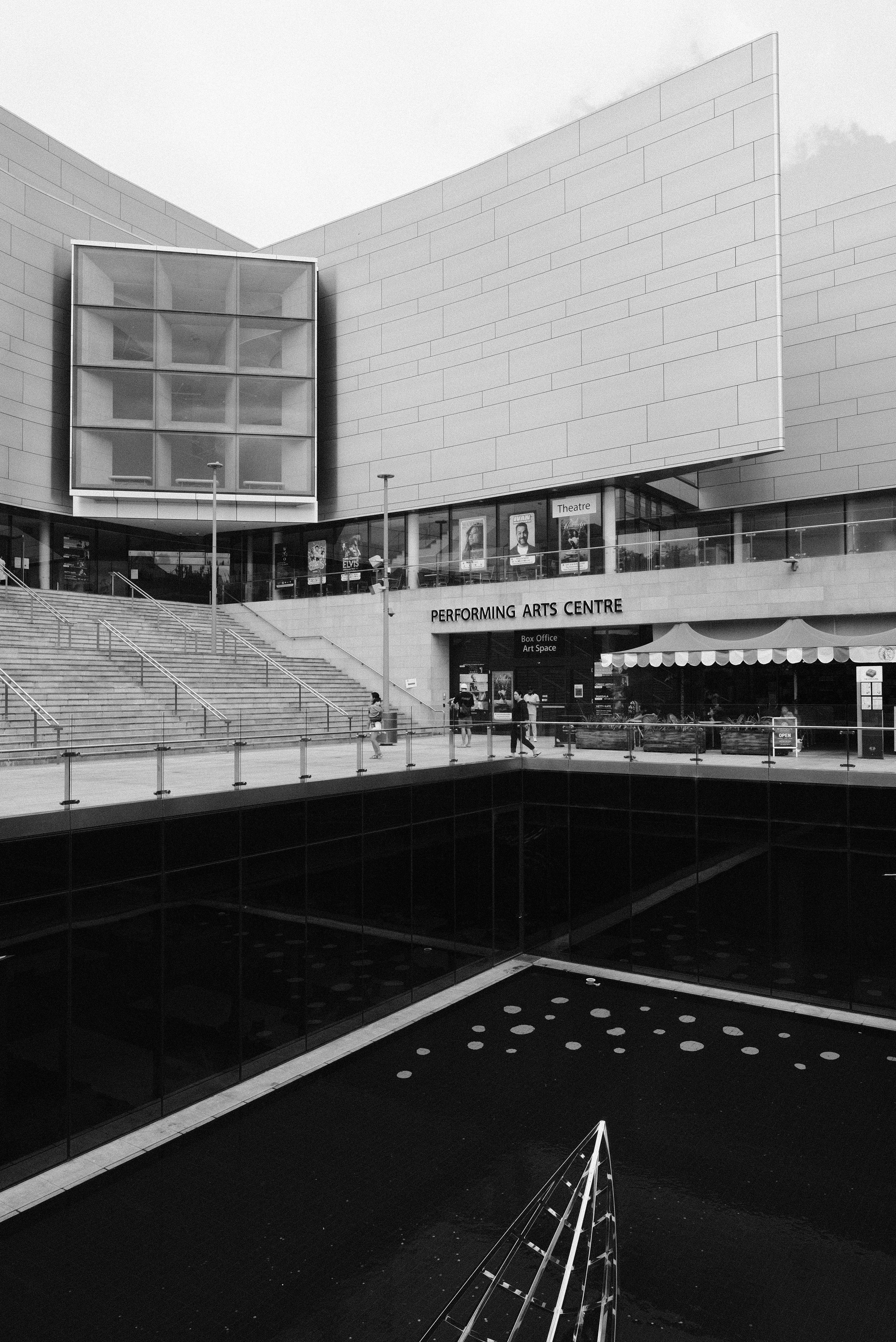 Monochrome Confluence: Glass, Stairs, and Activity at the Performing Arts Centre