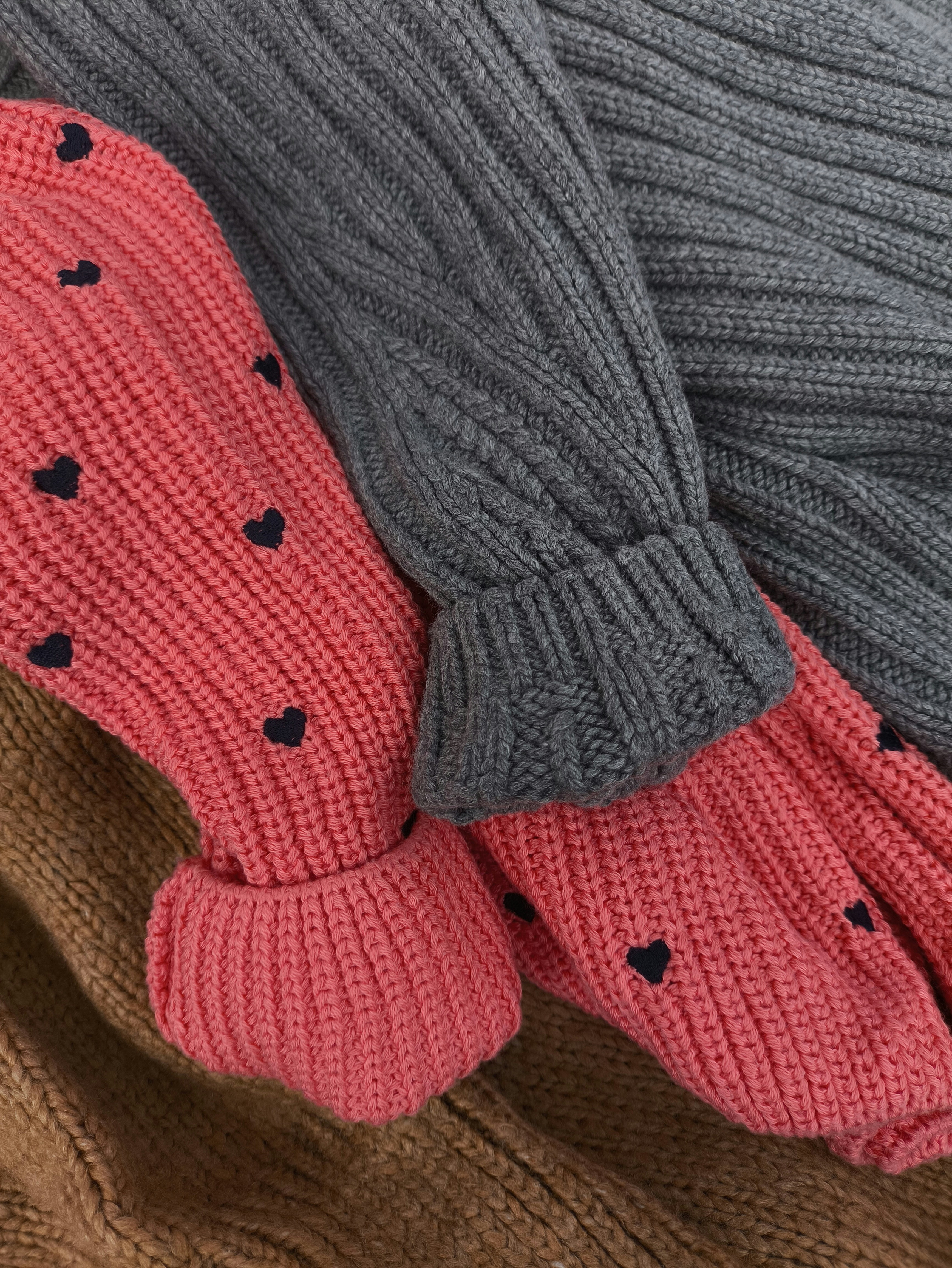 A pair of pink mittens sitting on top of a person's leg