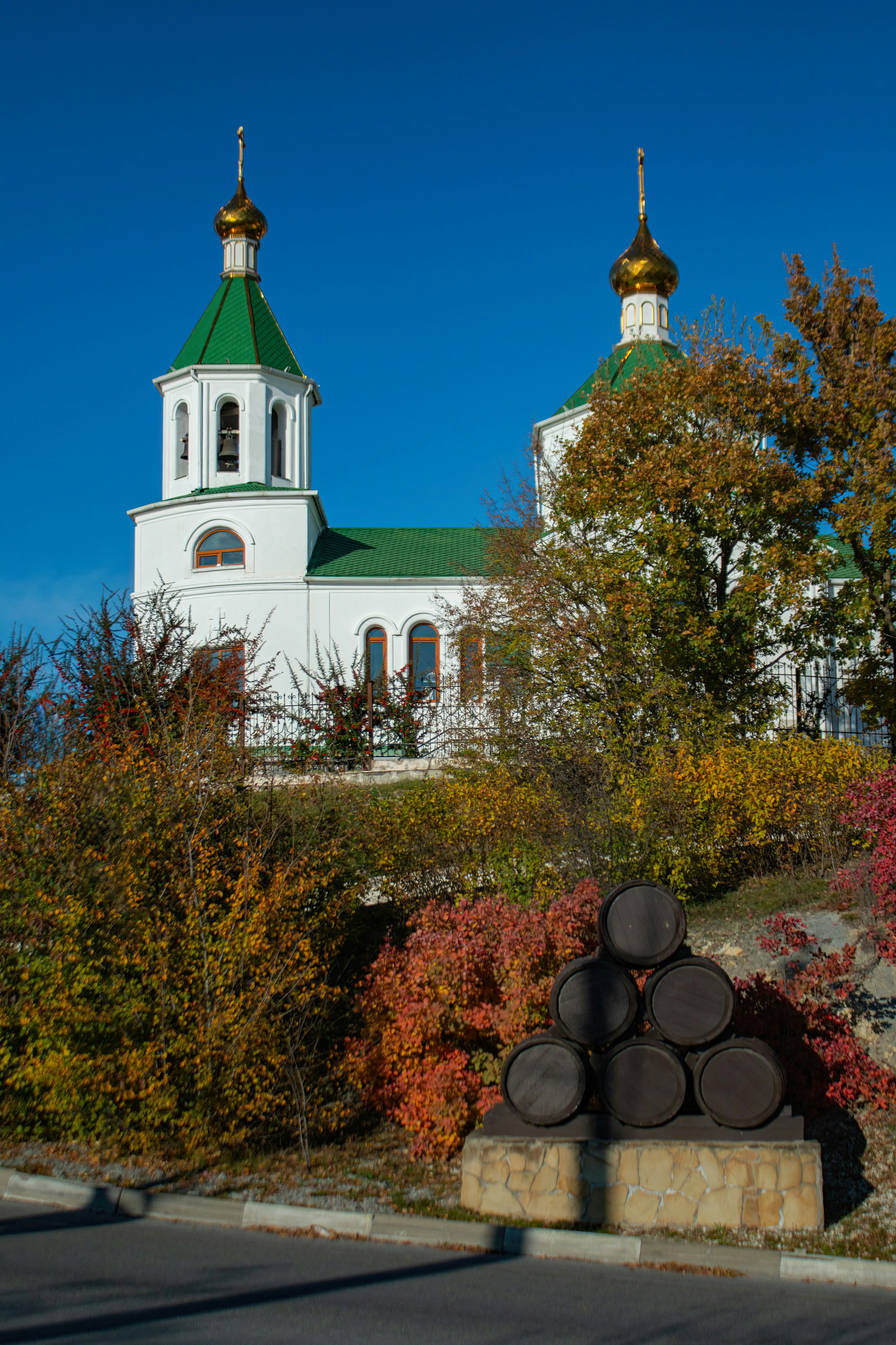 Autumn Foliage Frames a Green-Roofed Orthodox Church with Golden Domes