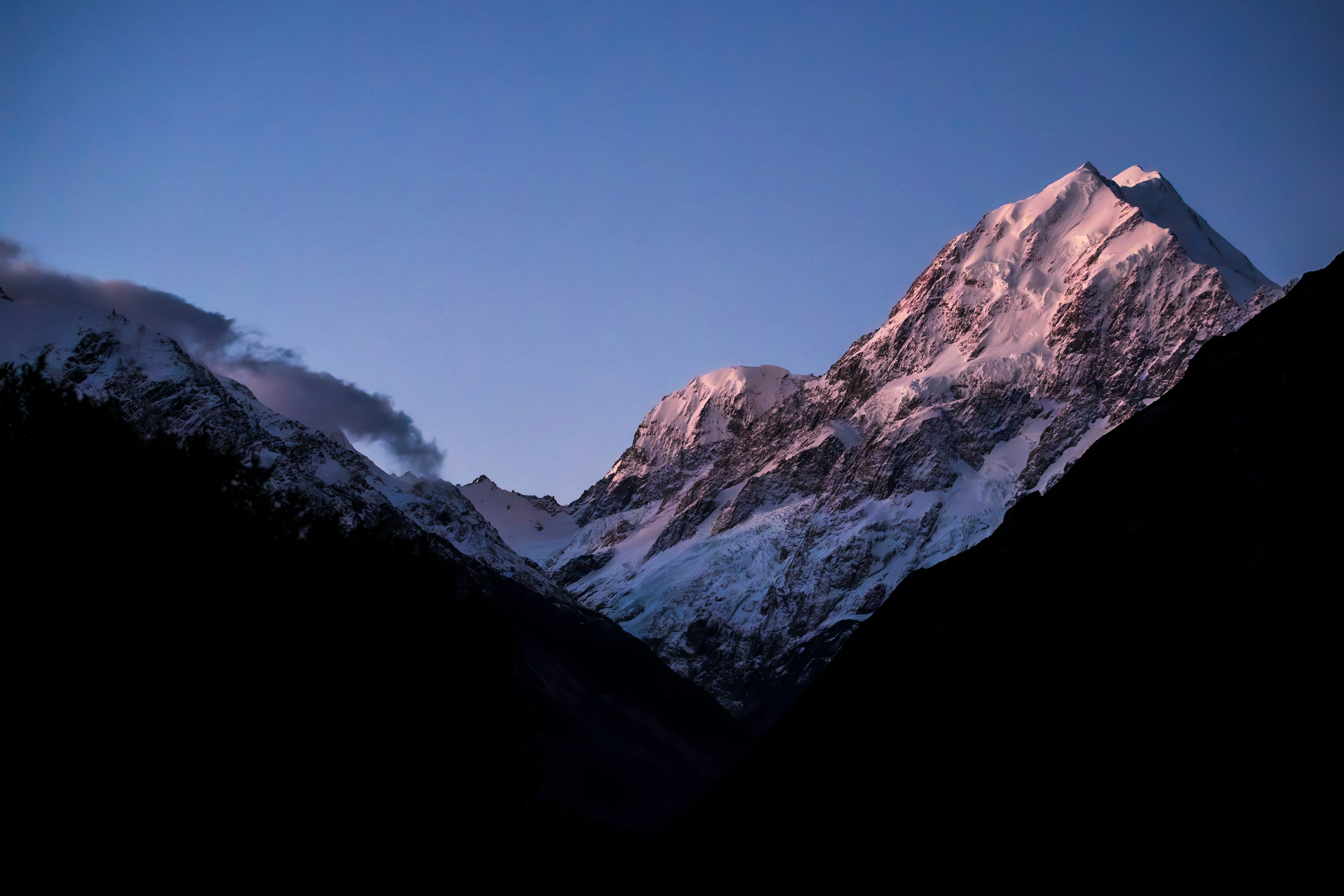 A snow covered mountain with a blue sky in the background photo – Free ...