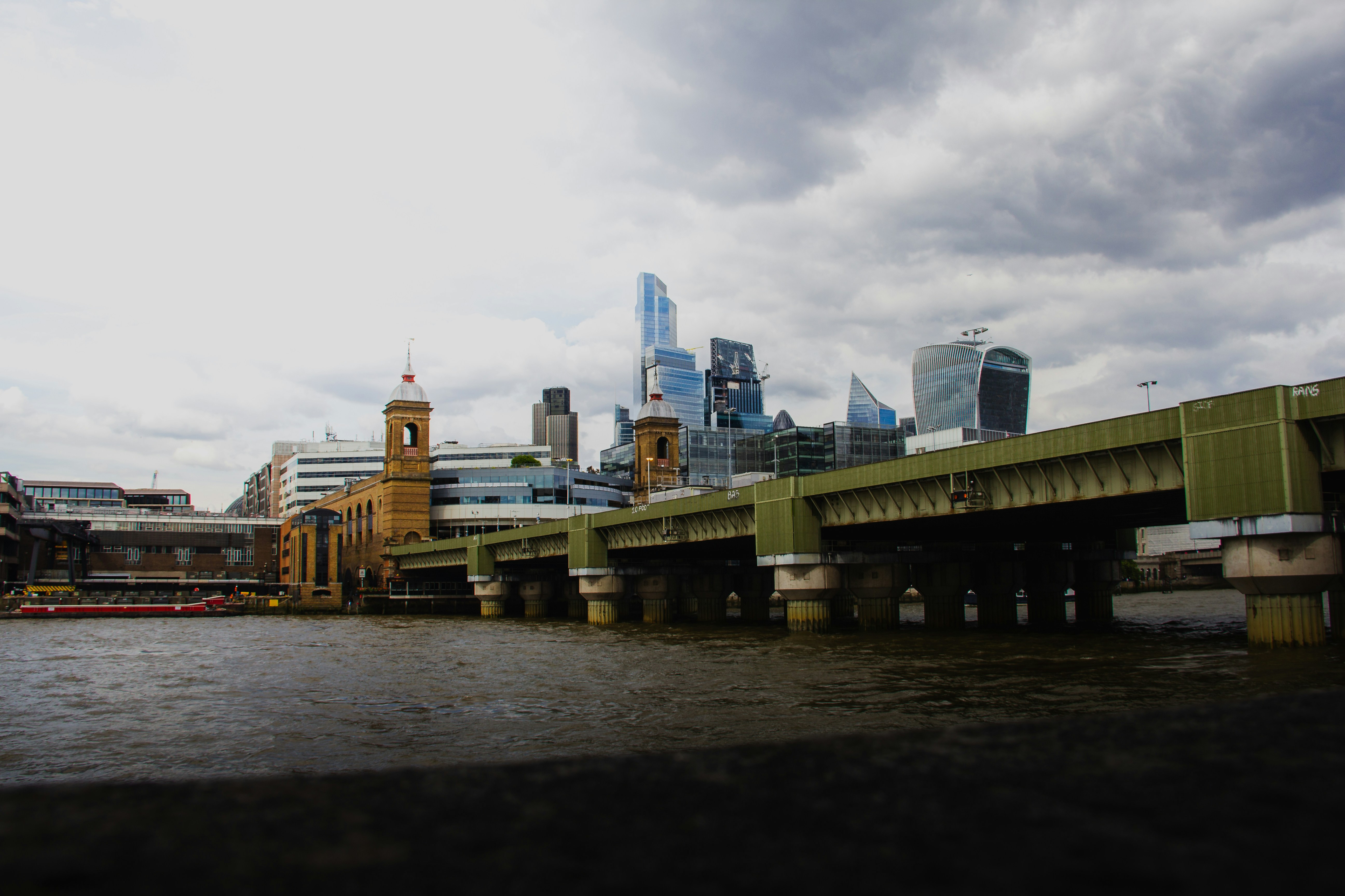 Green Bridge, Glass Skyline: Riverside Cityscape Beneath a Cloudy Sky