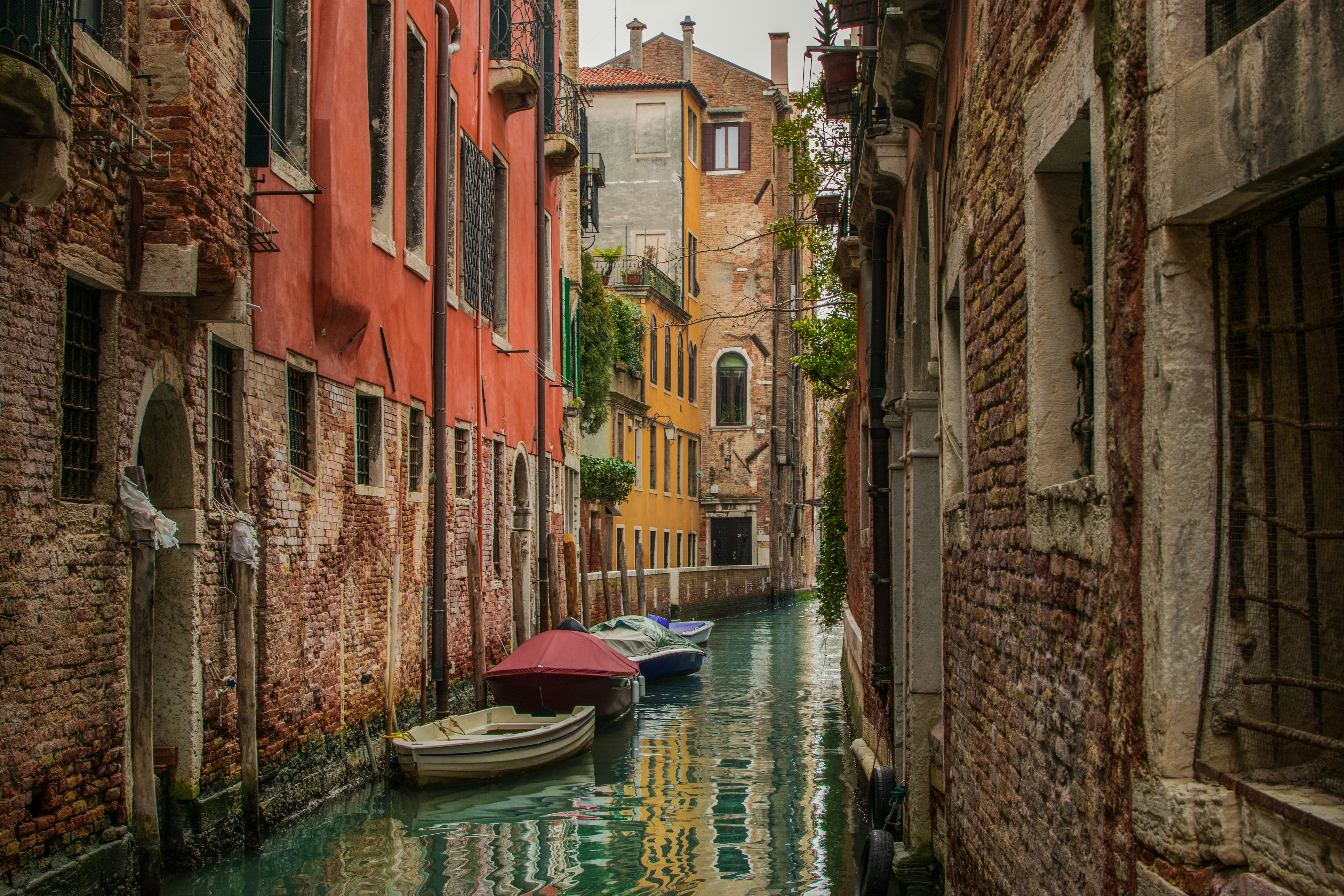 Narrow canal lined with colorful buildings and moored boats reflecting in calm water.