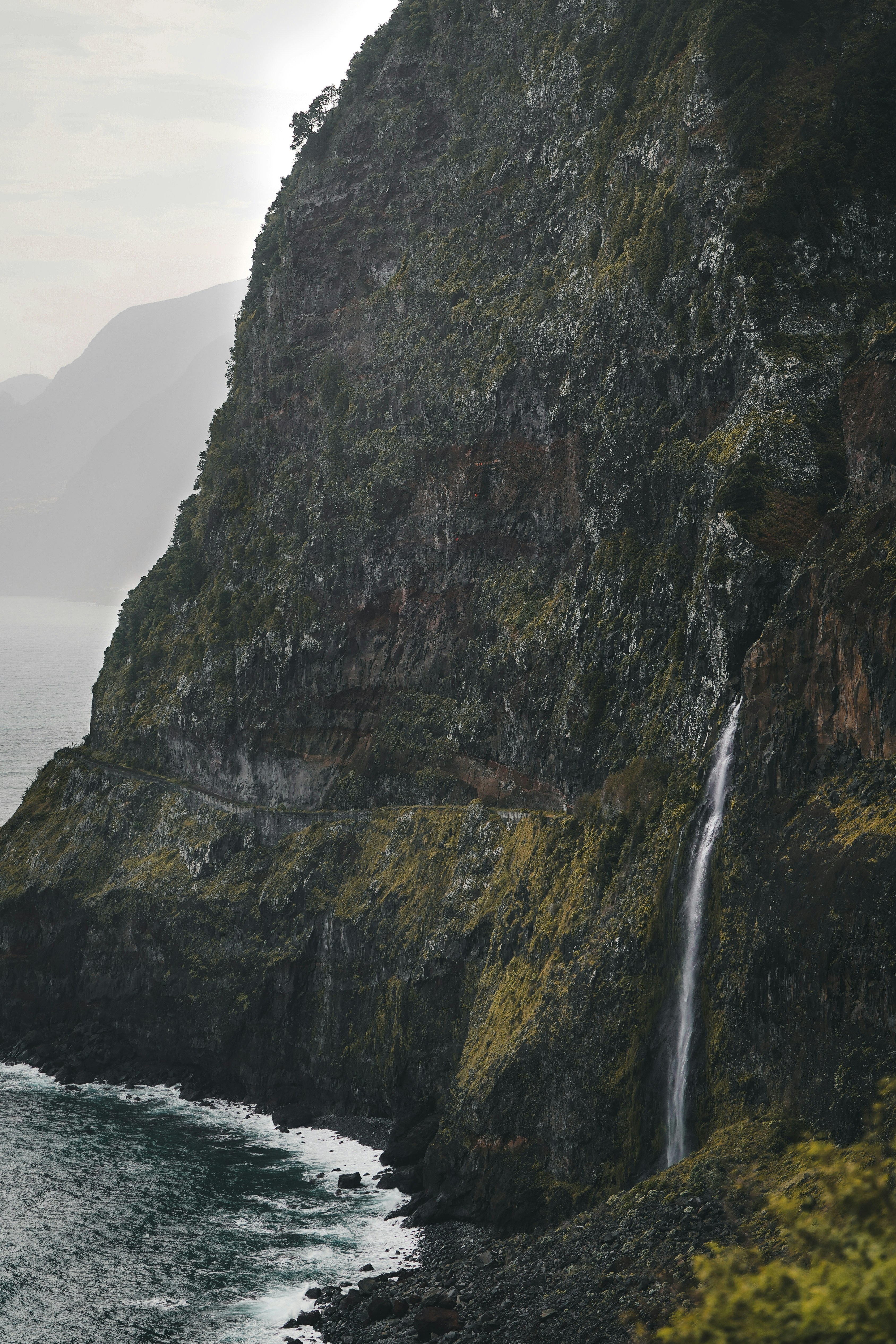 Vertical Veil: Moss-Streaked Cliff and the Narrow Waterfall