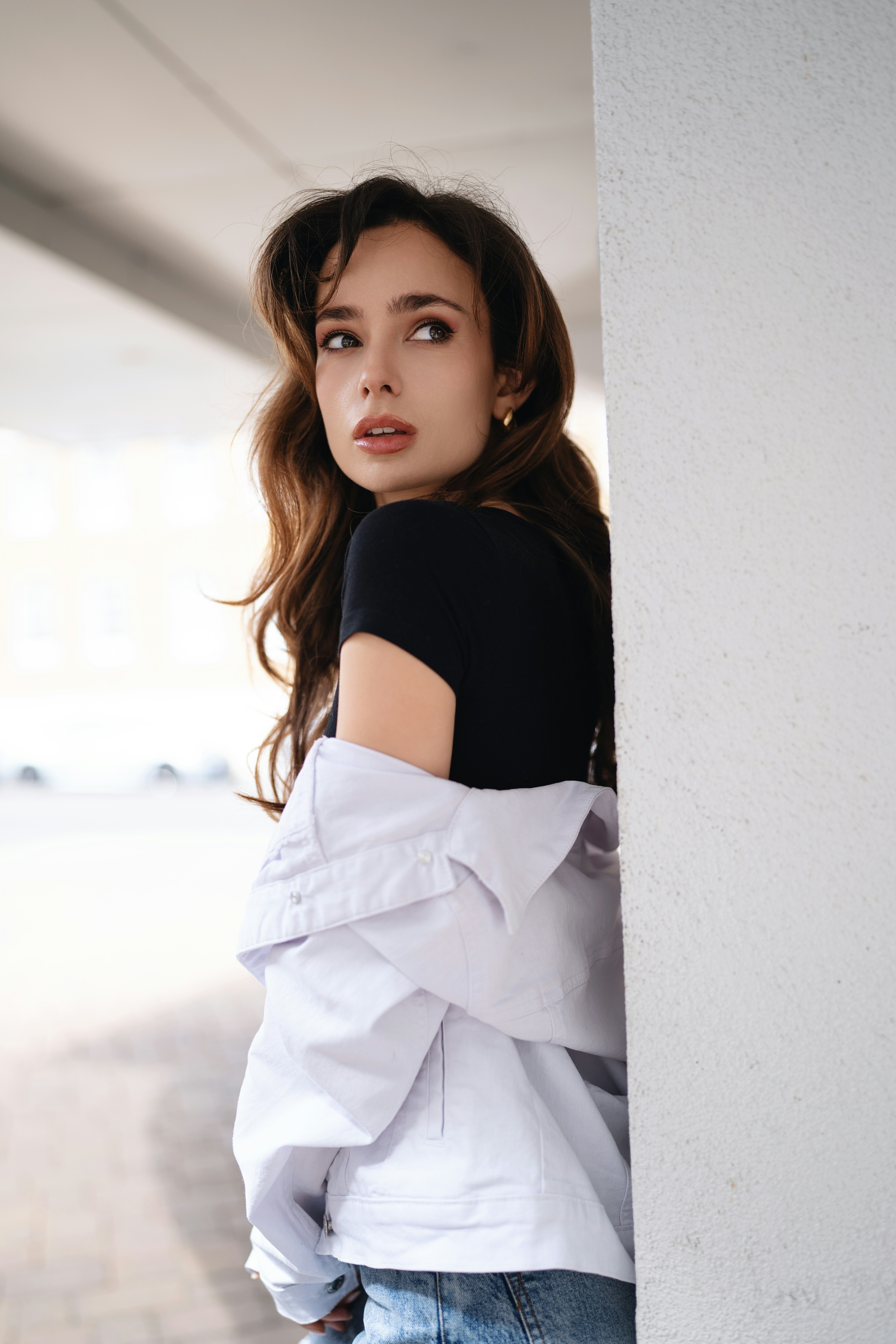 A woman leaning against a wall with her arms wrapped around her ...
