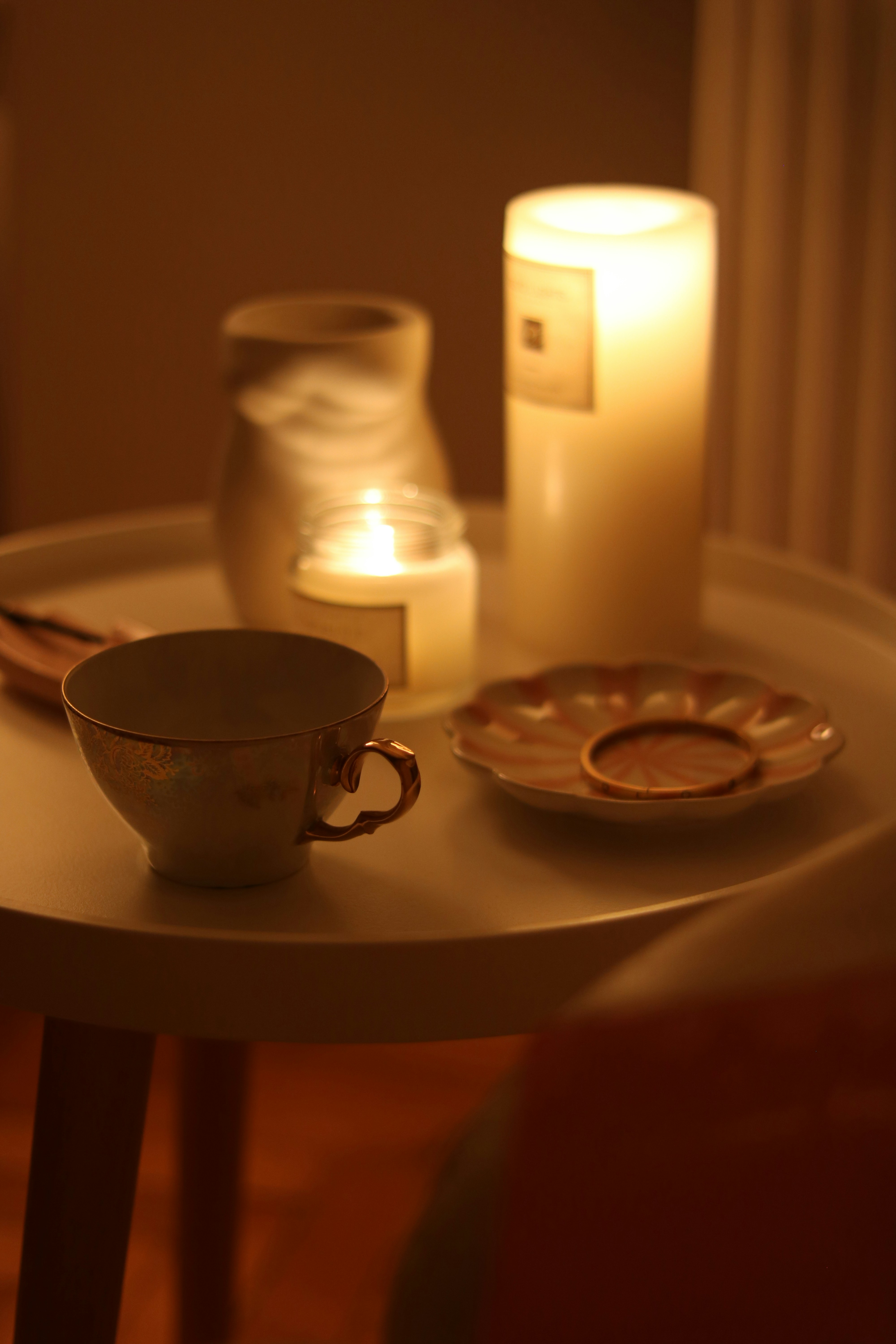 Candlelit Quietude: A Teacup and Tiny Dish on a White Table