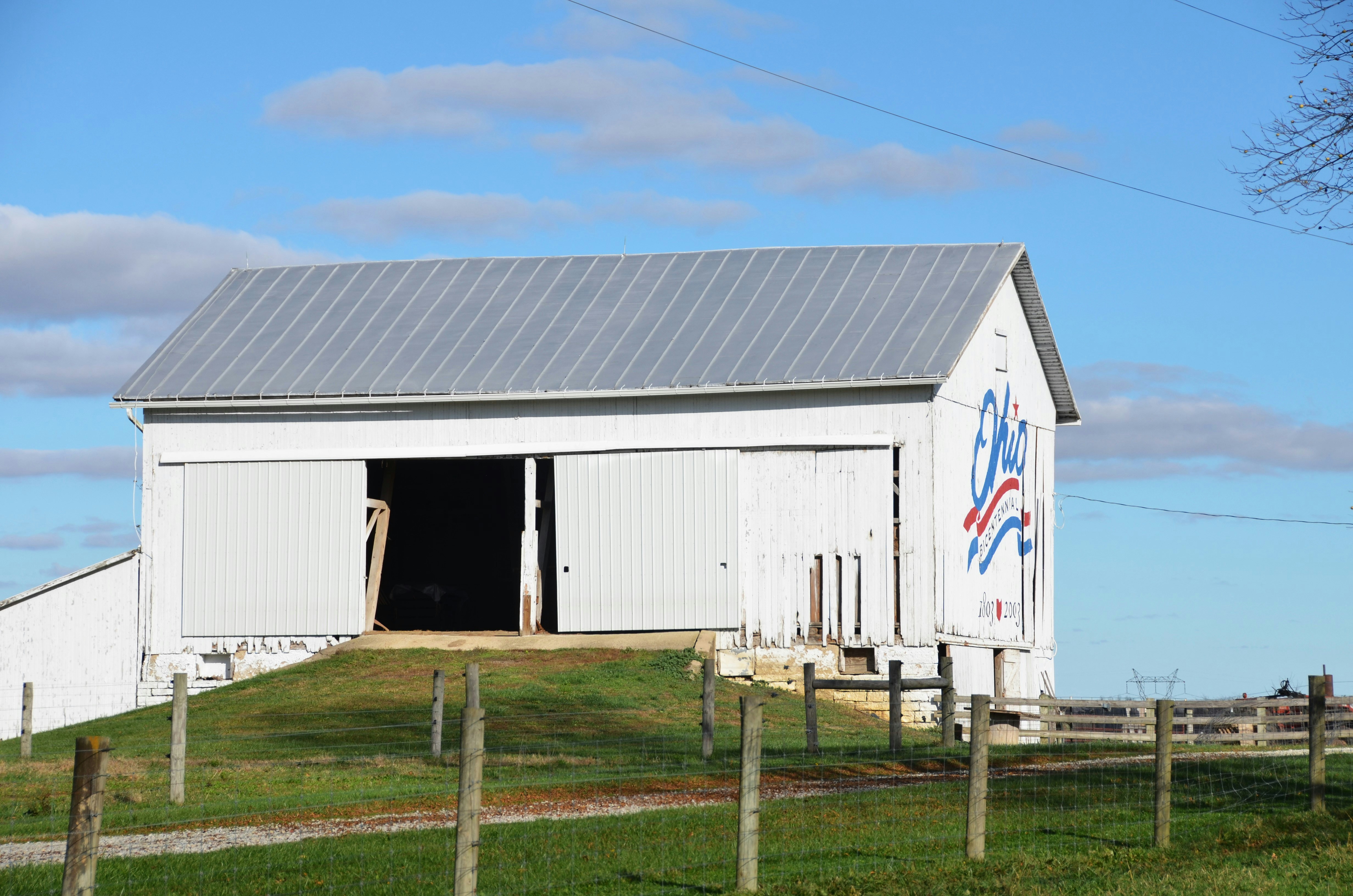 A large white barn sitting on top of a lush green field photo – Free ...