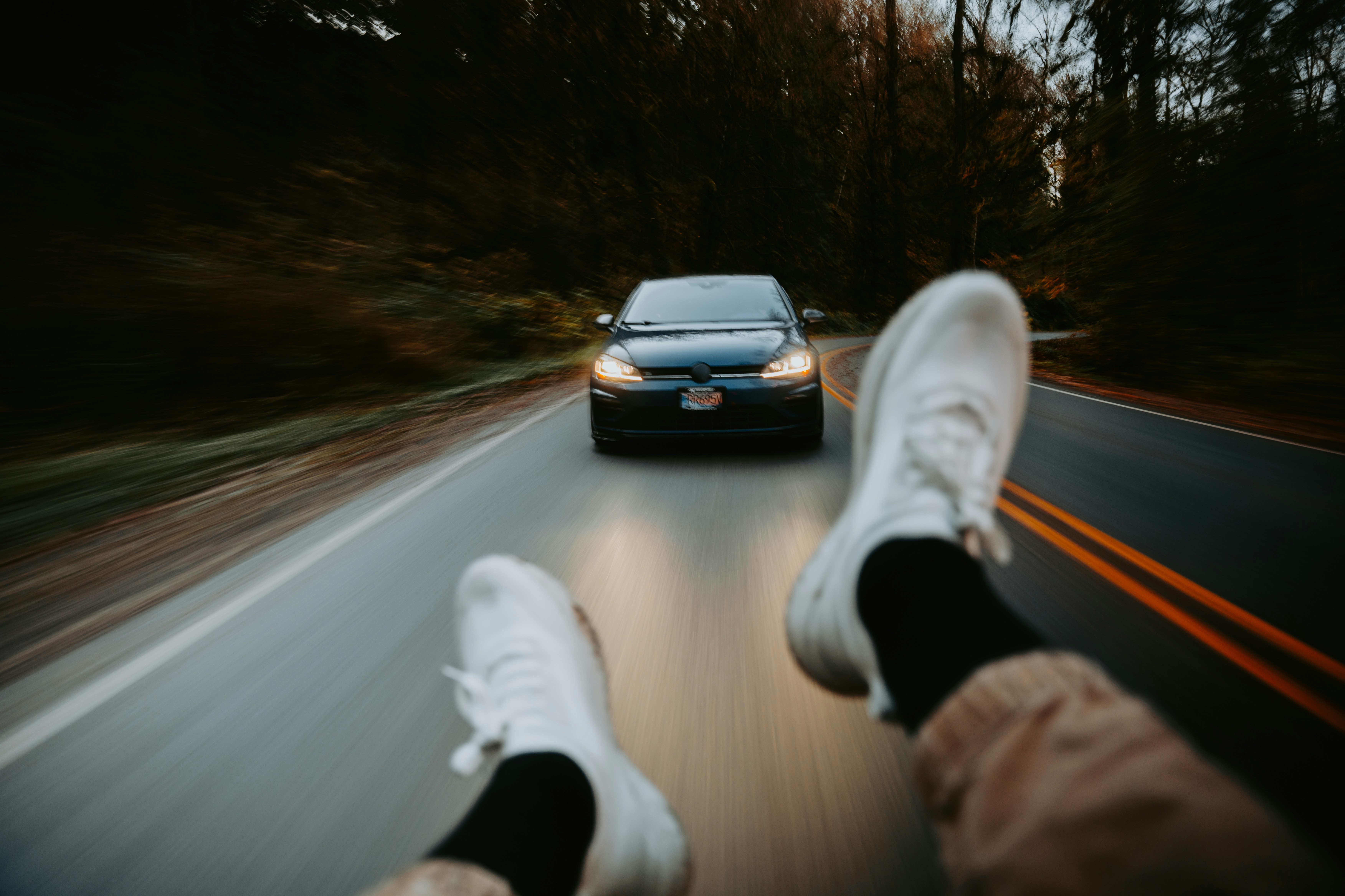 A car driving down a road next to a person's feet photo – Free Car ...