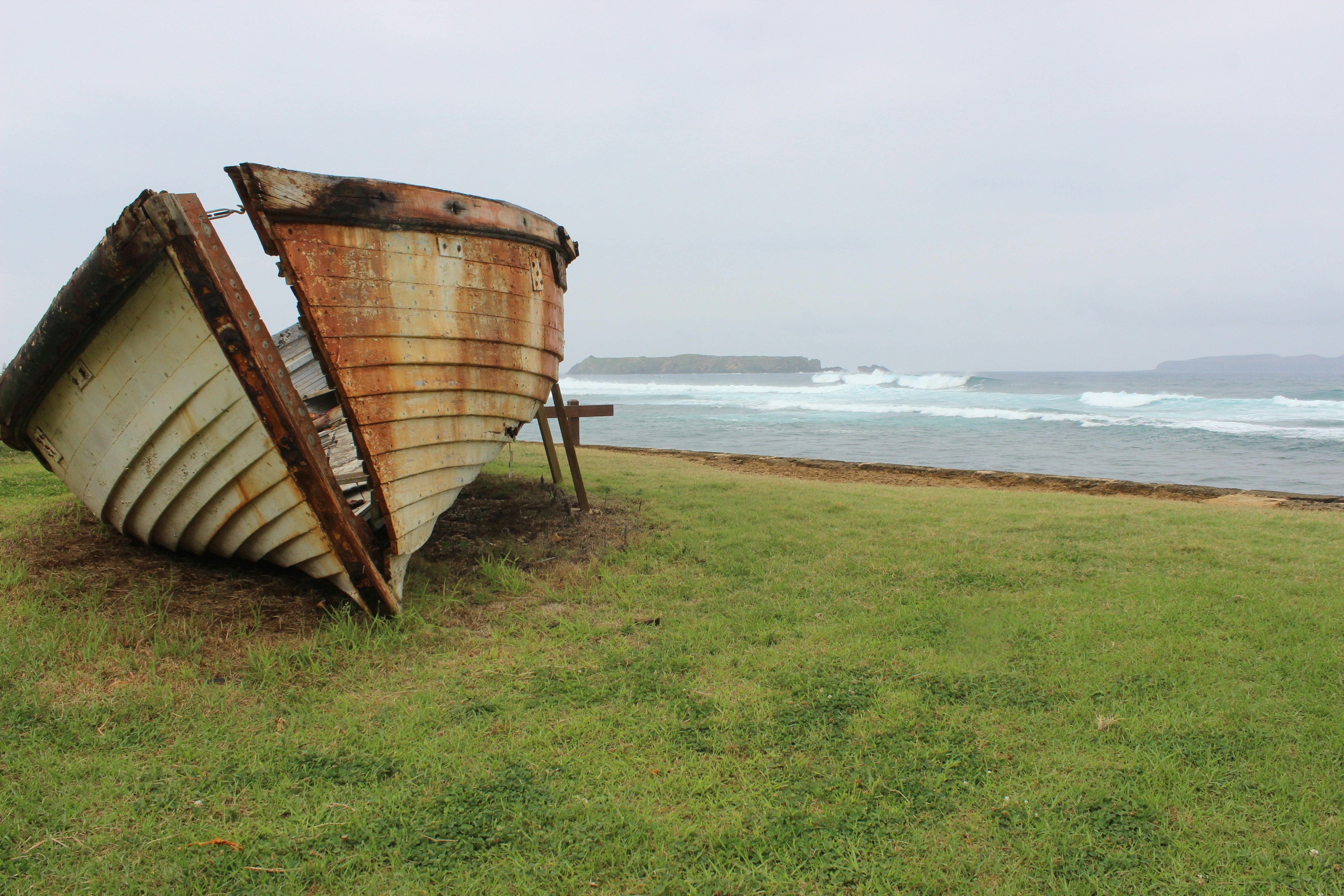 Rusting Bow of Time: A Coastal Vessel Resting on Grass by the Sea