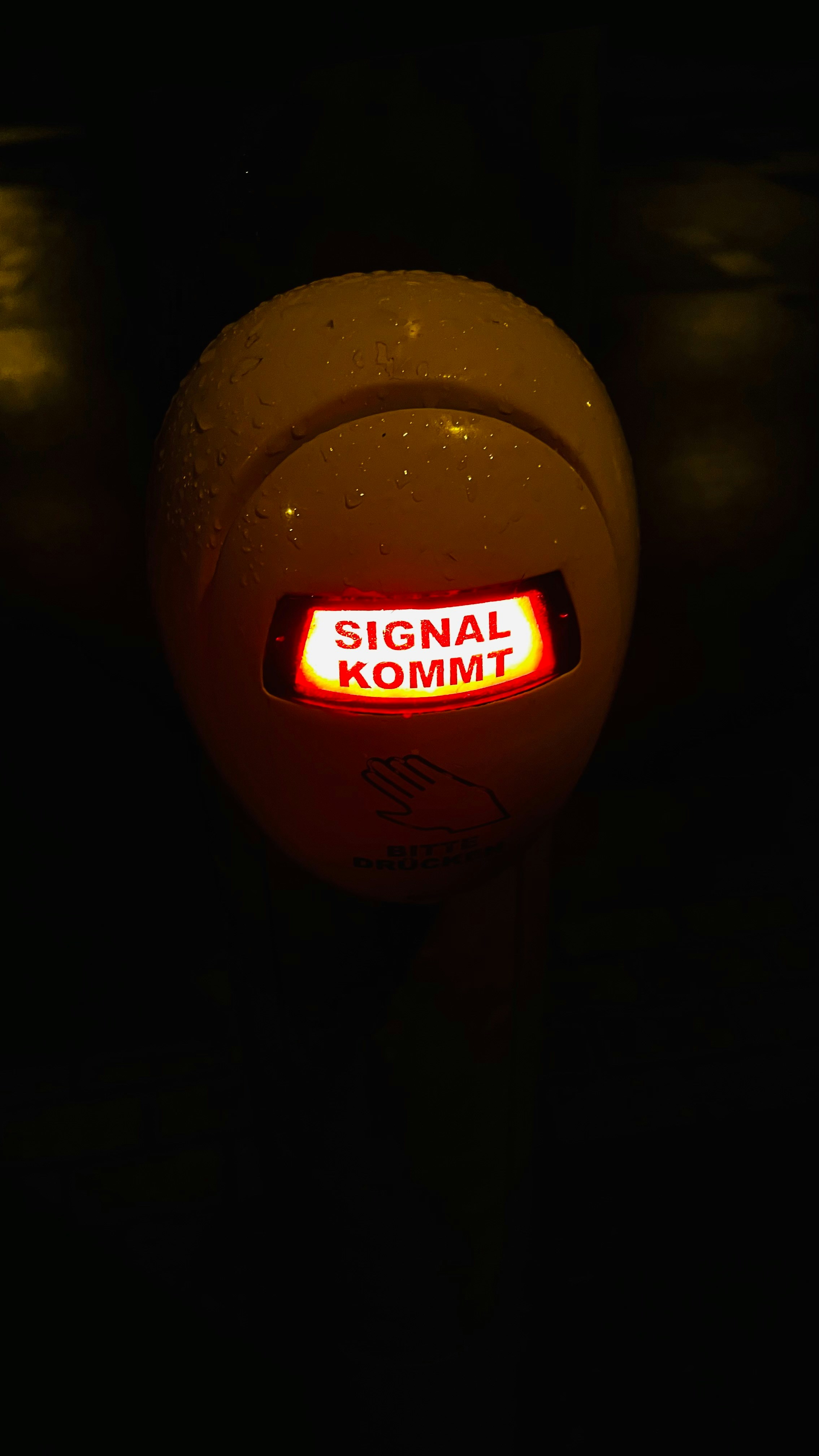 Red Signal Glow: A Rain-Speckled Push Button Illuminates a Quiet Night