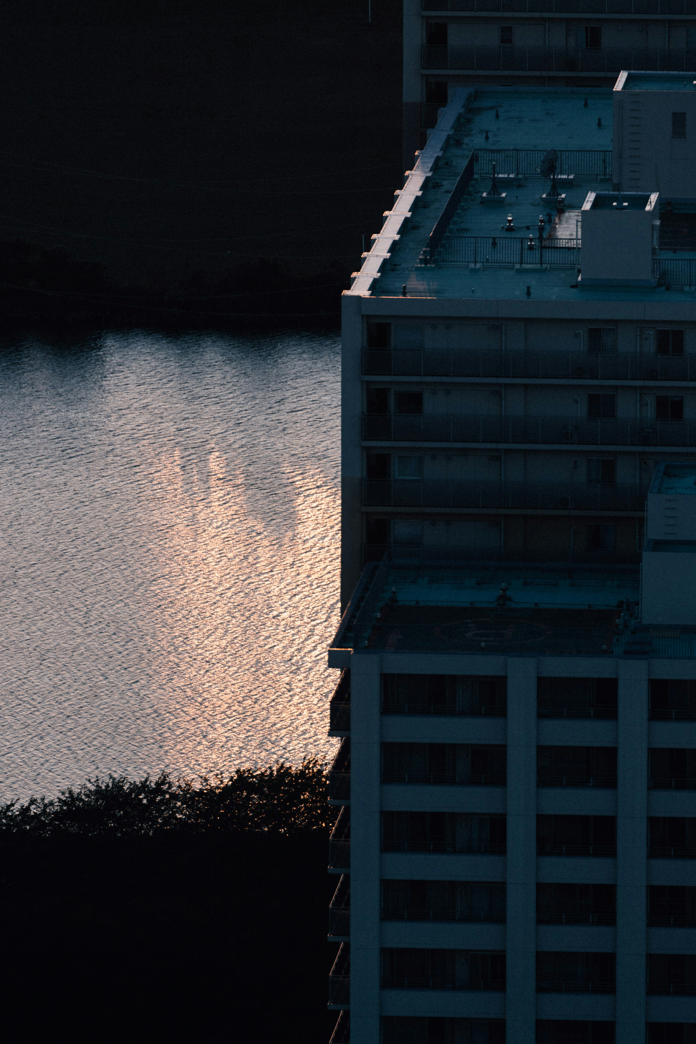 A tall building sitting next to a body of water photo – Free Japan ...