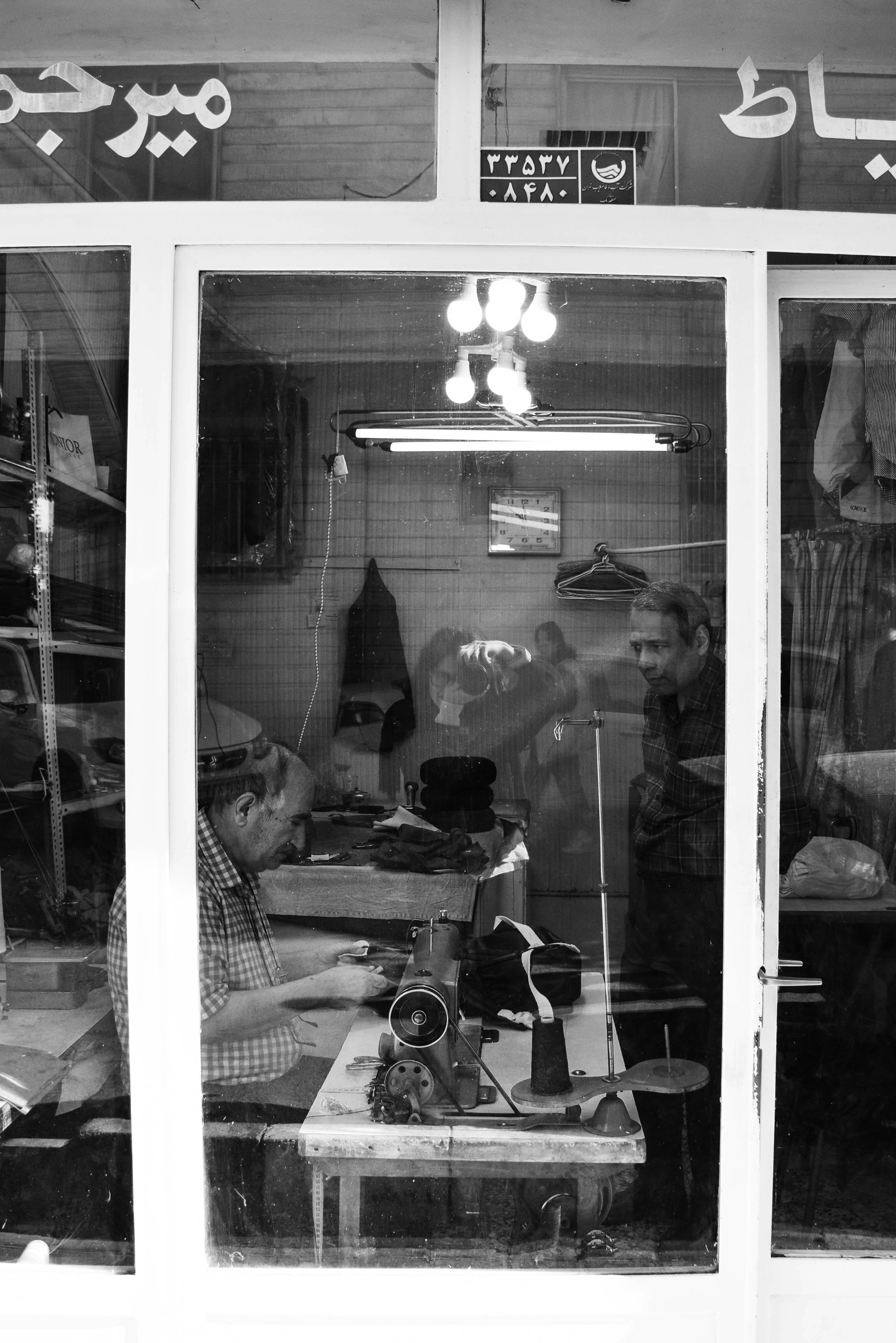 Glassfront Atelier: Two Tailors at Work Behind a Shop Window