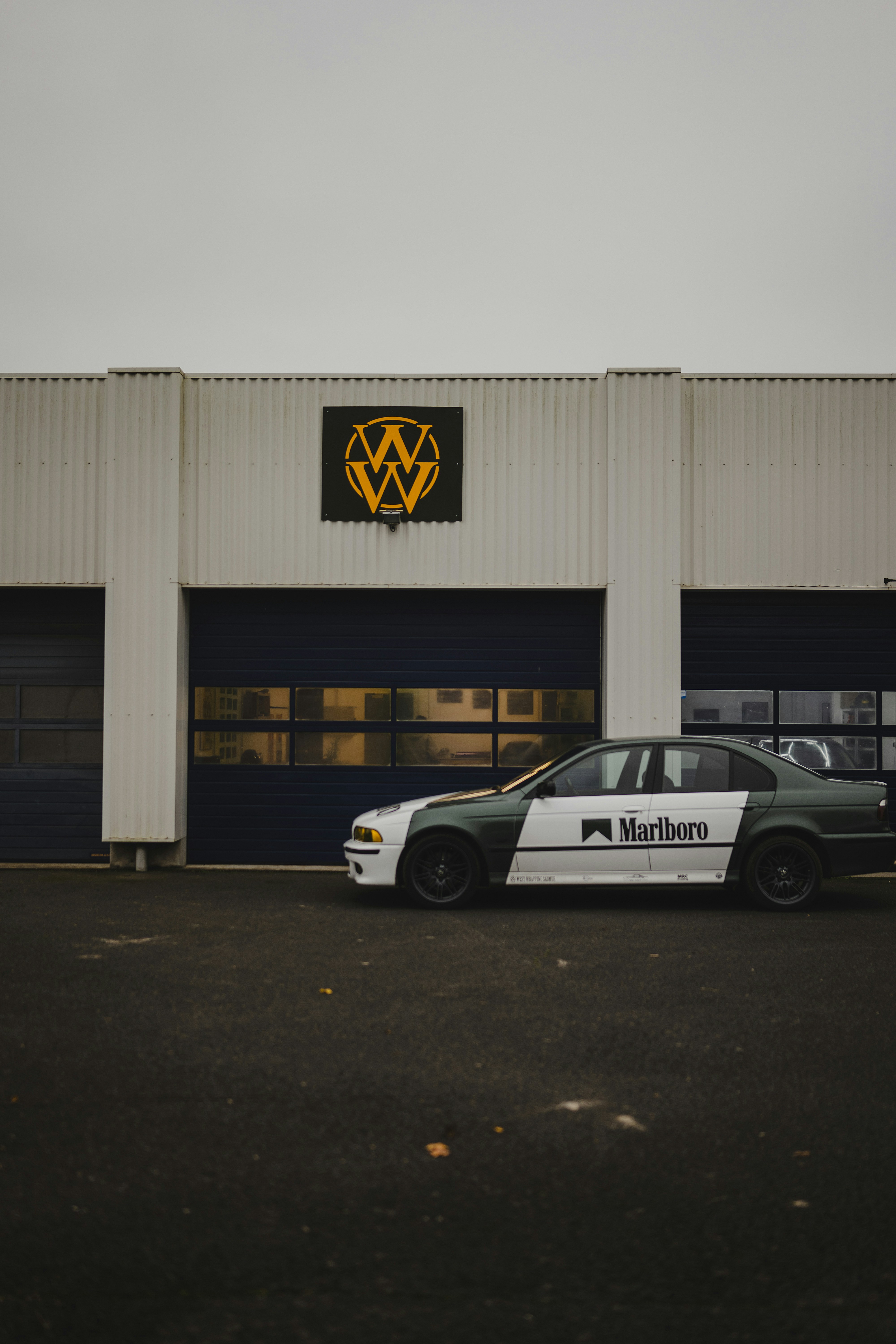 Industrial Crest Encounter: A Marlboro-Wrapped Sedan Before a Bold Yellow VW Emblem