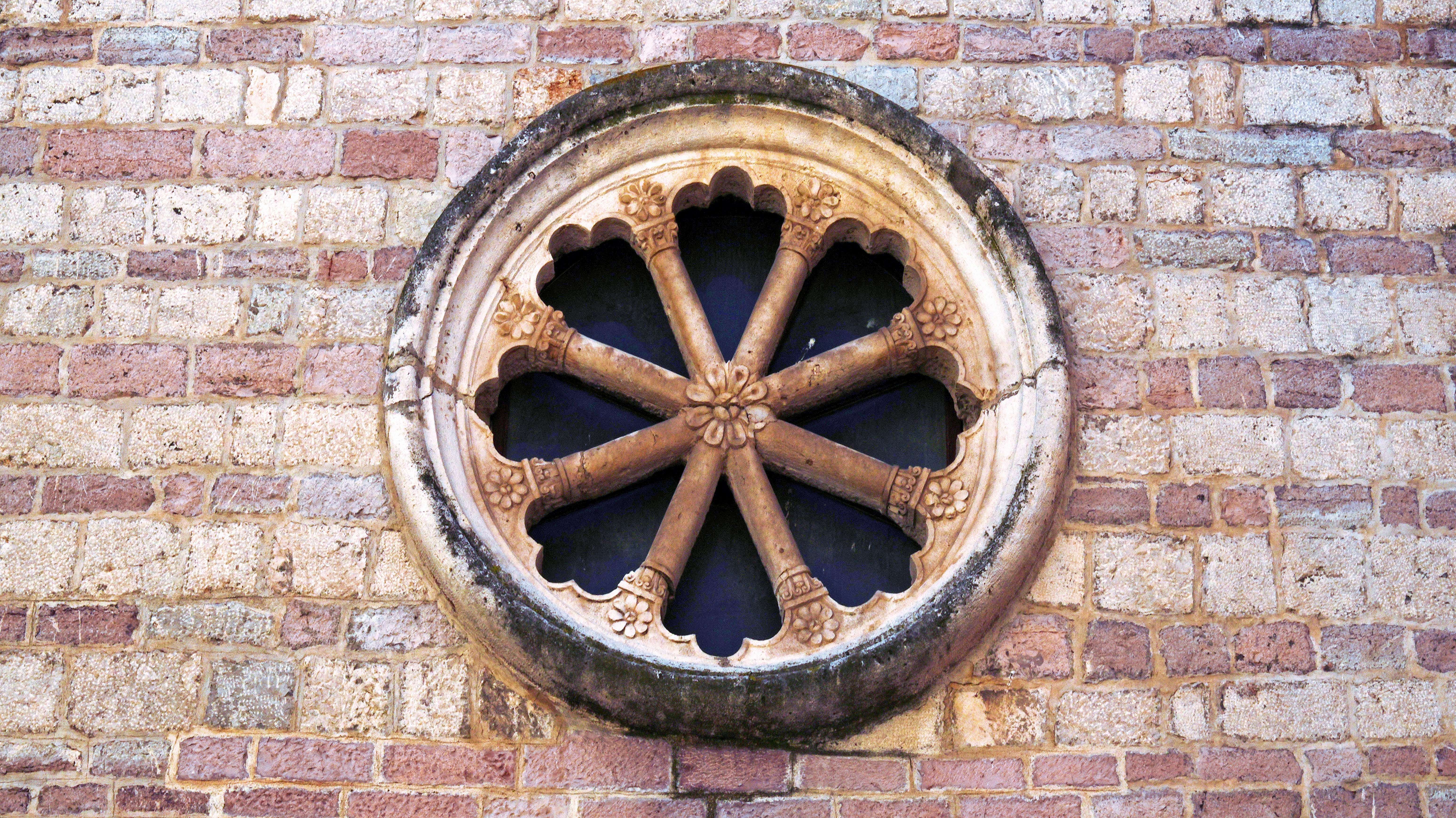 The Stone Wheel: Weathered Circular Vent Framed by Brickwork