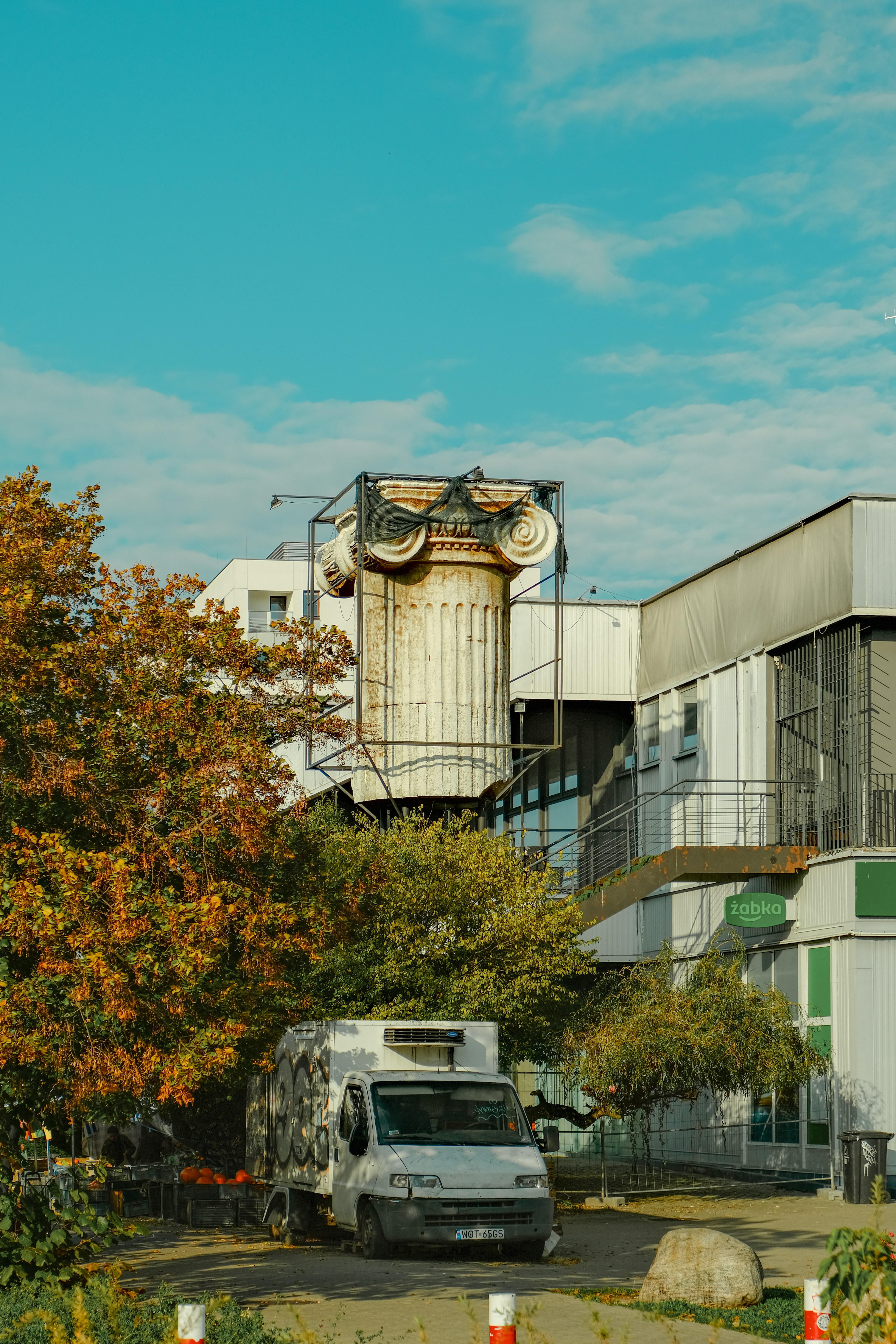 Corinthian Cylinder Amid Scaffolding: Autumn Light in a City Yard