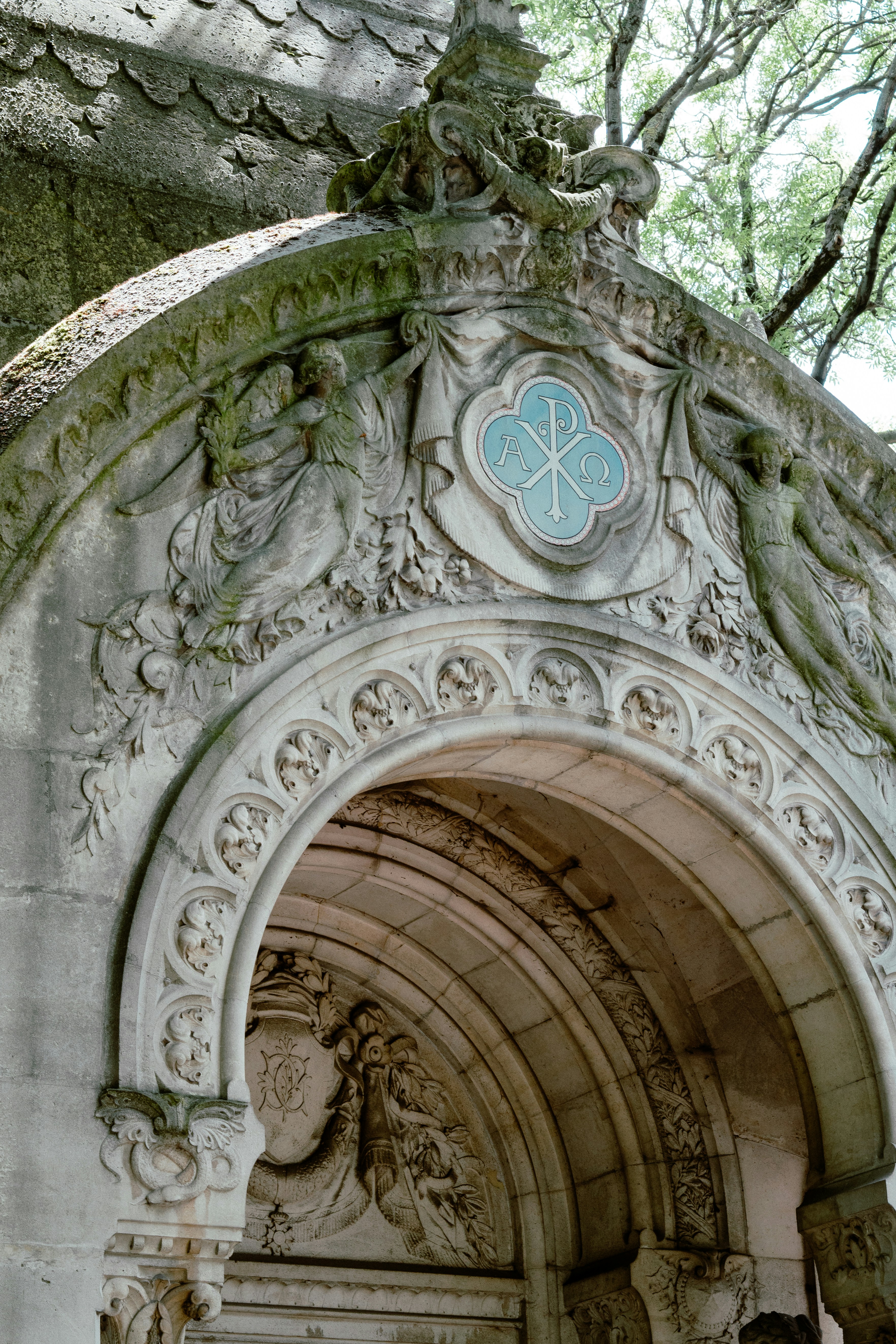 Blue Monogram Medallion Anchors a Mossy Stone Archway