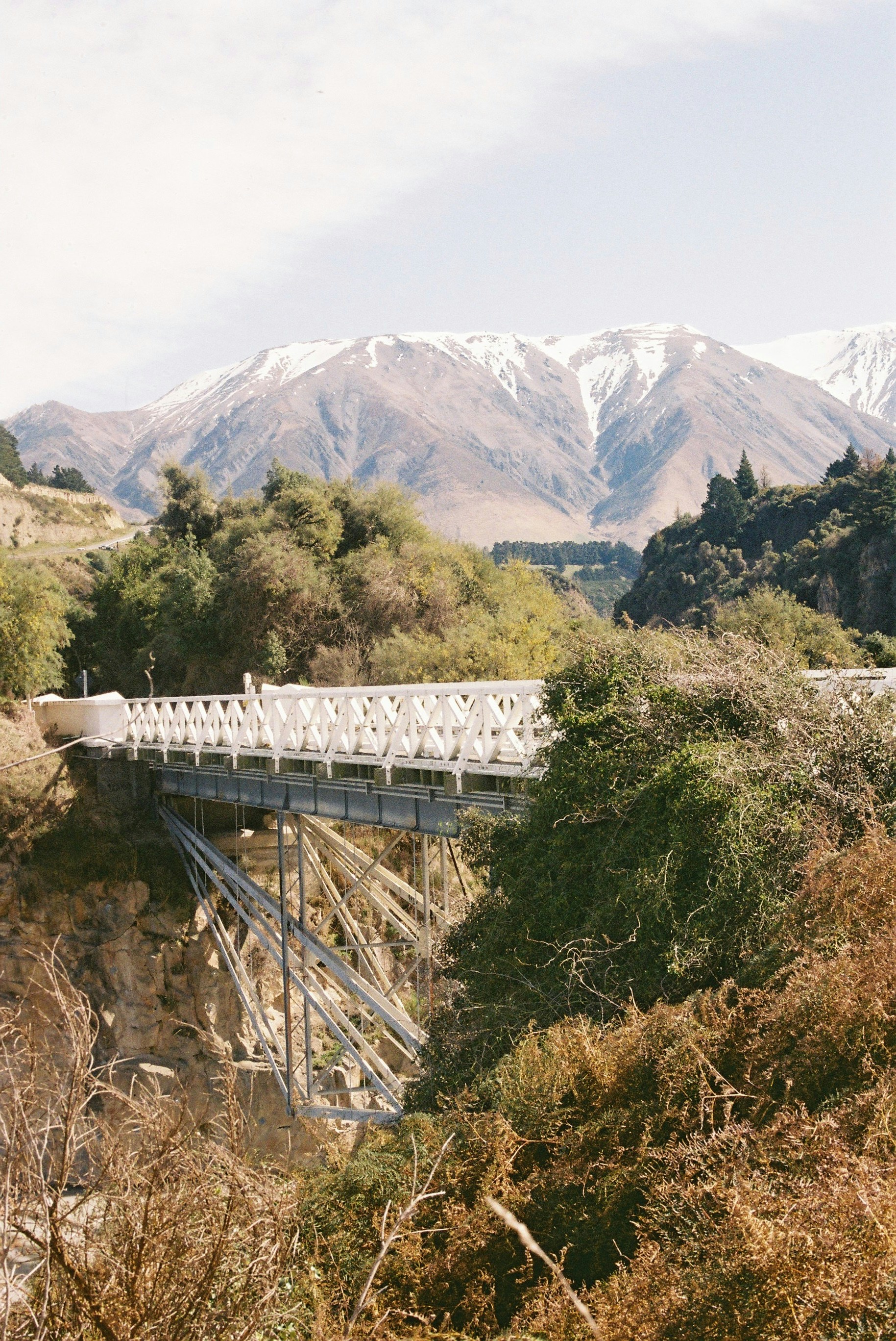 Lattice Bridge Crossing a Verdant Gorge Beneath Snow-Dusted Peaks