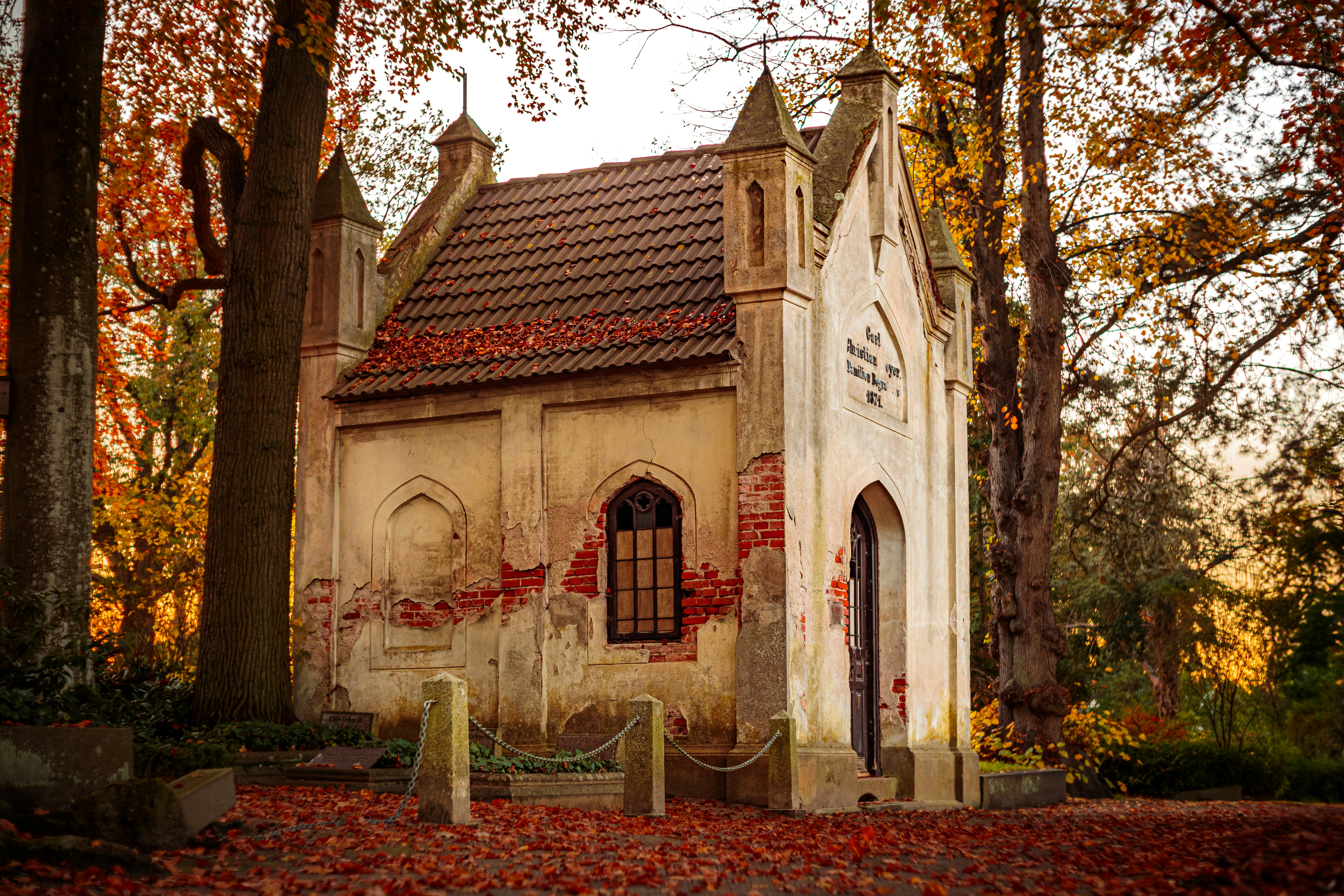 Old crypt building in a cemetery during autumn | A small church in the middle of a forest